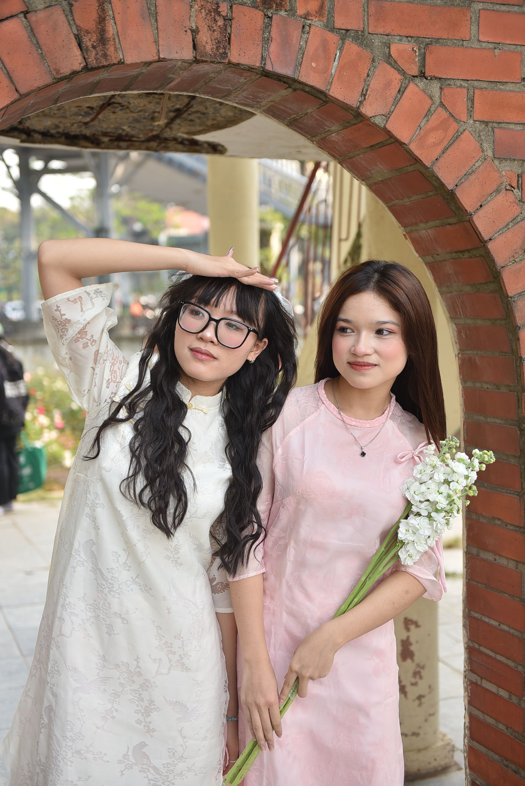 Two Women in Traditional Dresses Under Brick Archway · Free Stock Photo