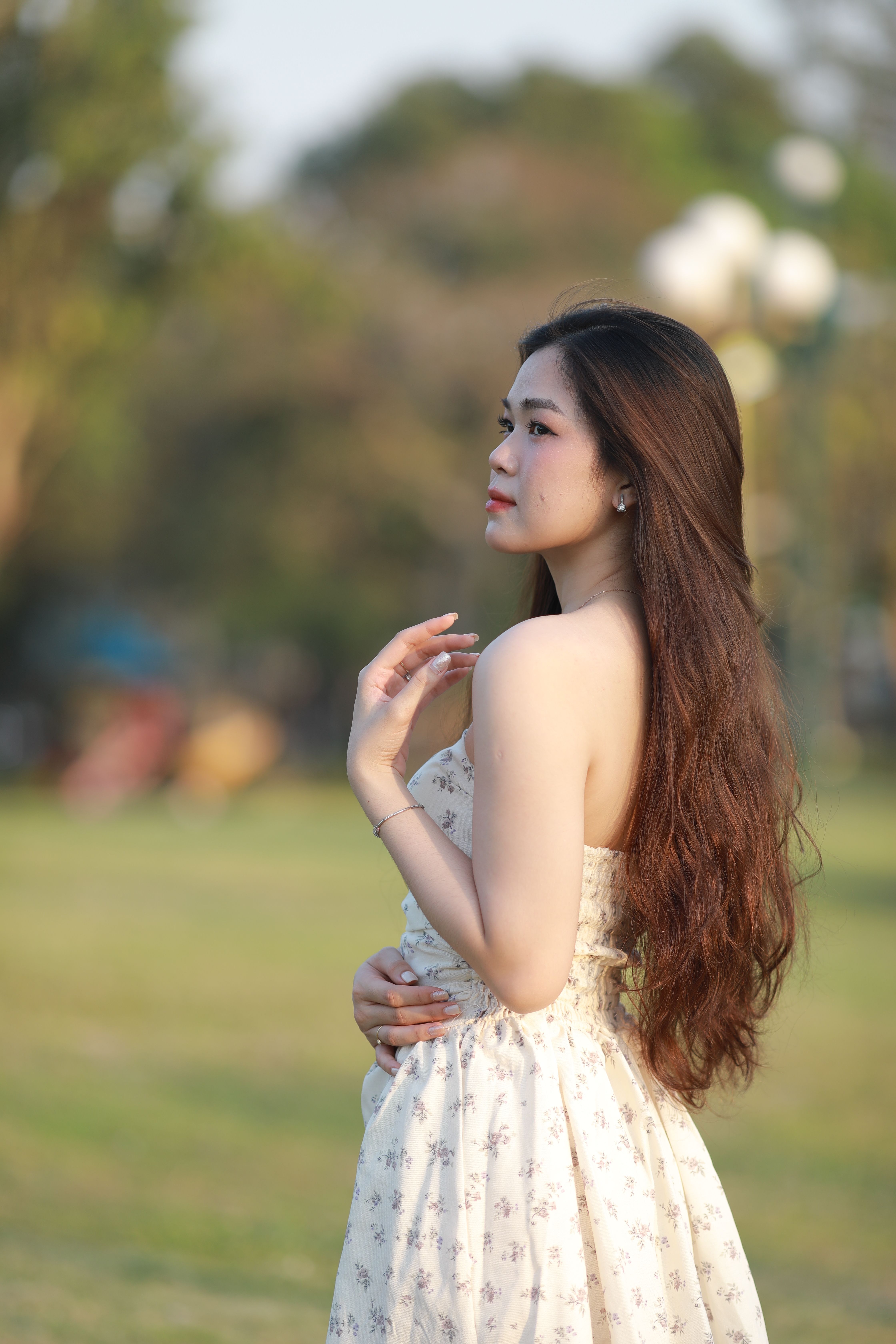 Elegant Young Woman Posing in Sunlit Park · Free Stock Photo