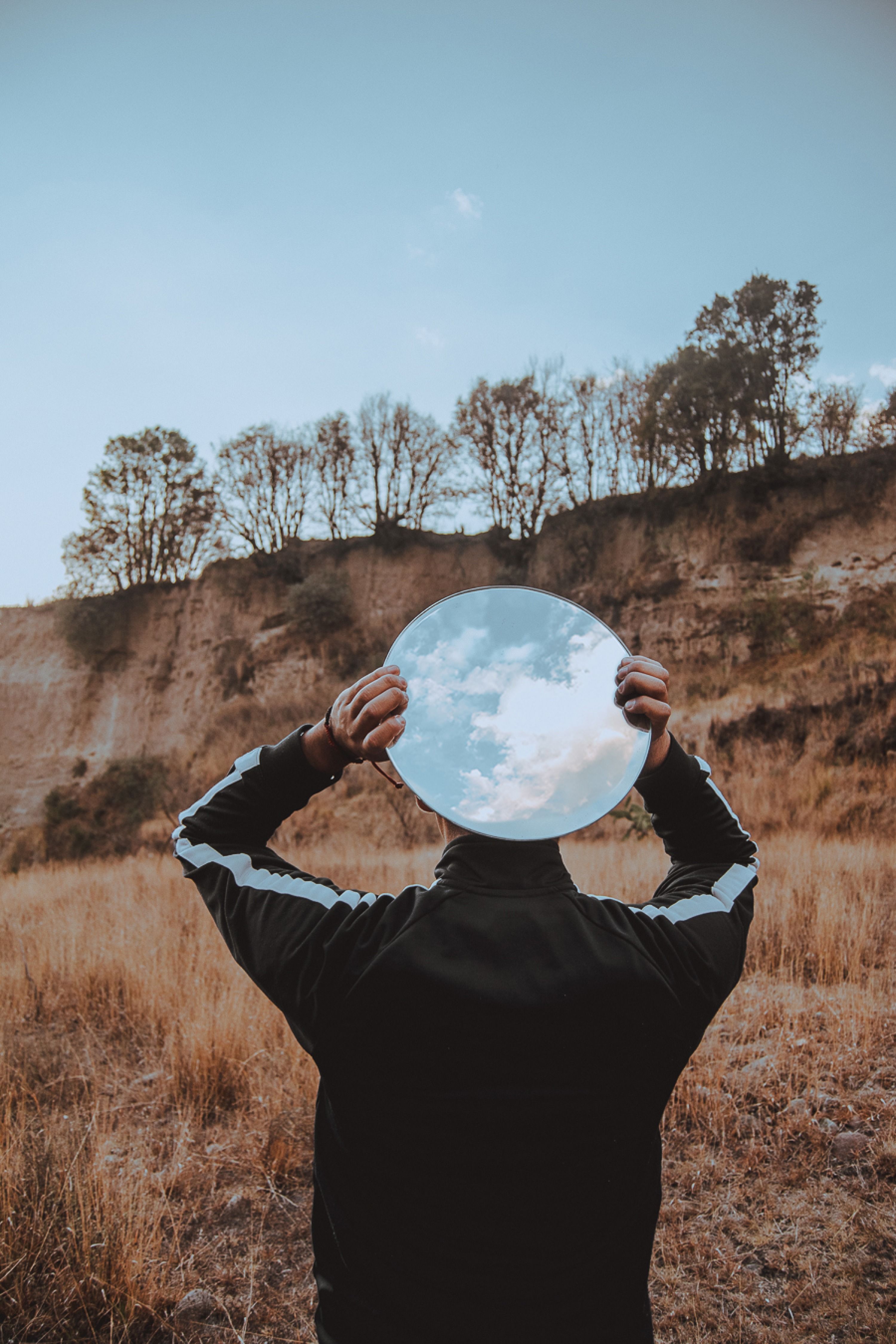 Man Holding Mirror Reflecting Sky Outdoors · Free Stock Photo