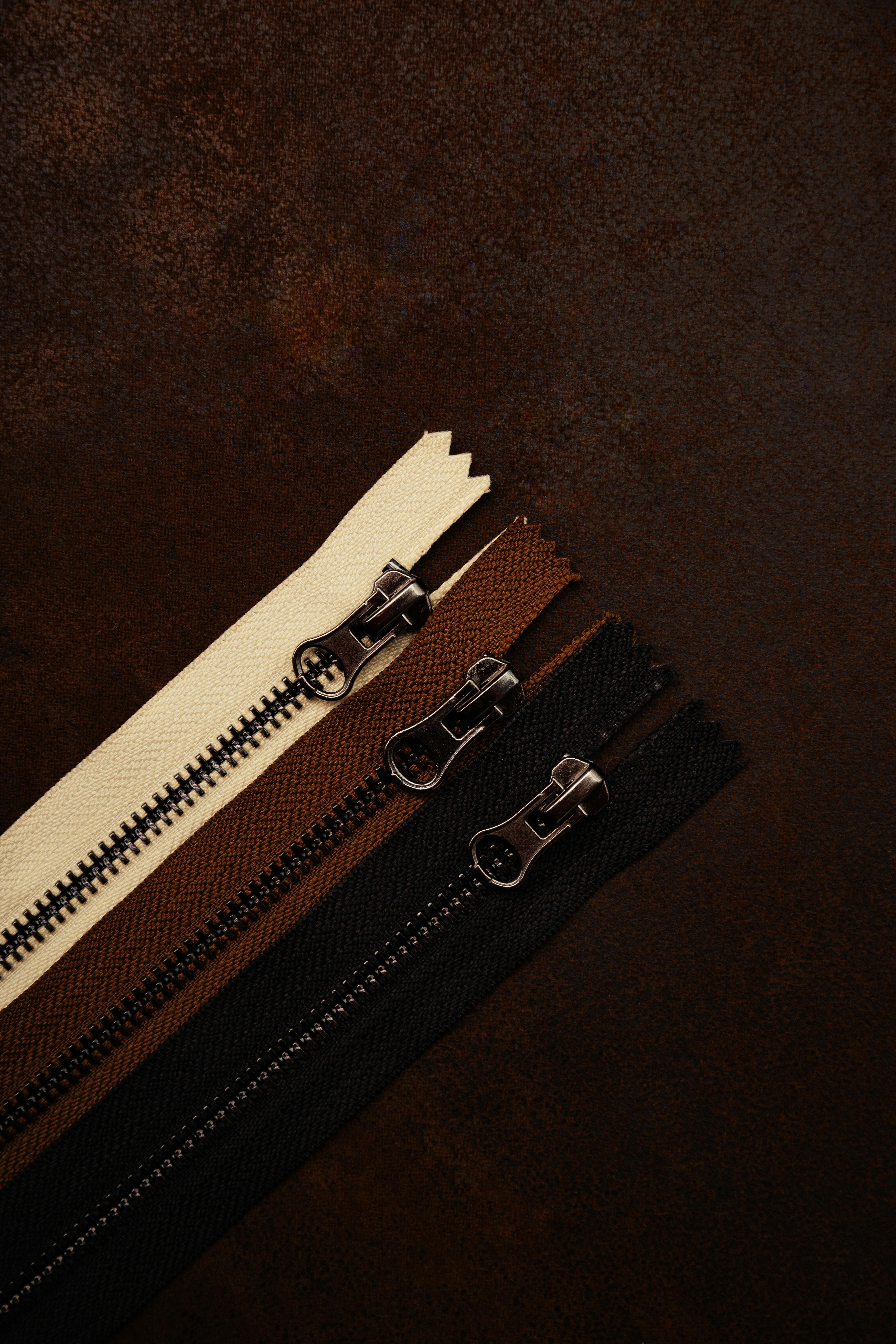 Close-Up of Assorted Zippers on Dark Fabric · Free Stock Photo