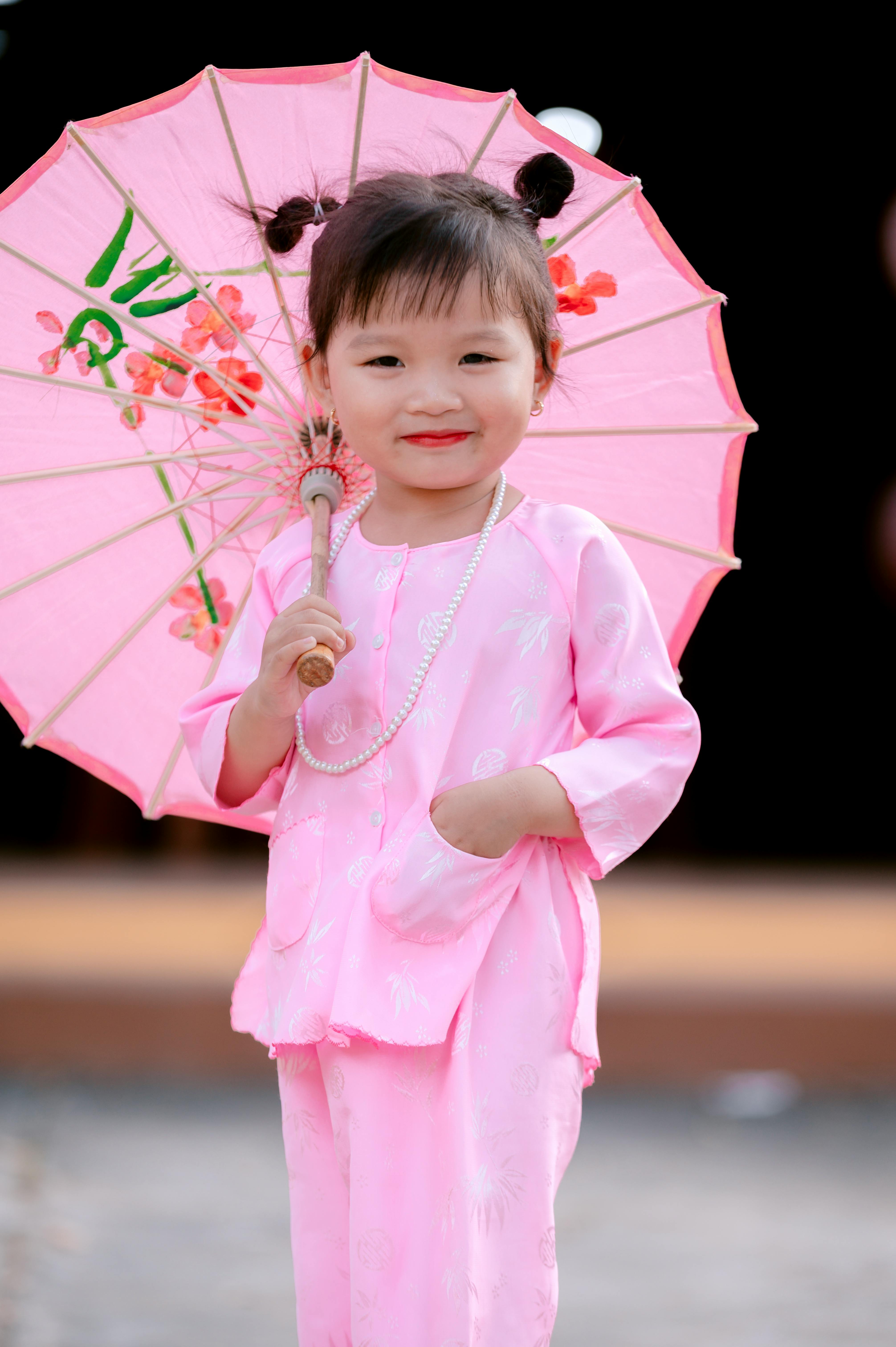 Adorable Child in Traditional Pink Outfit with Umbrella · Free Stock Photo