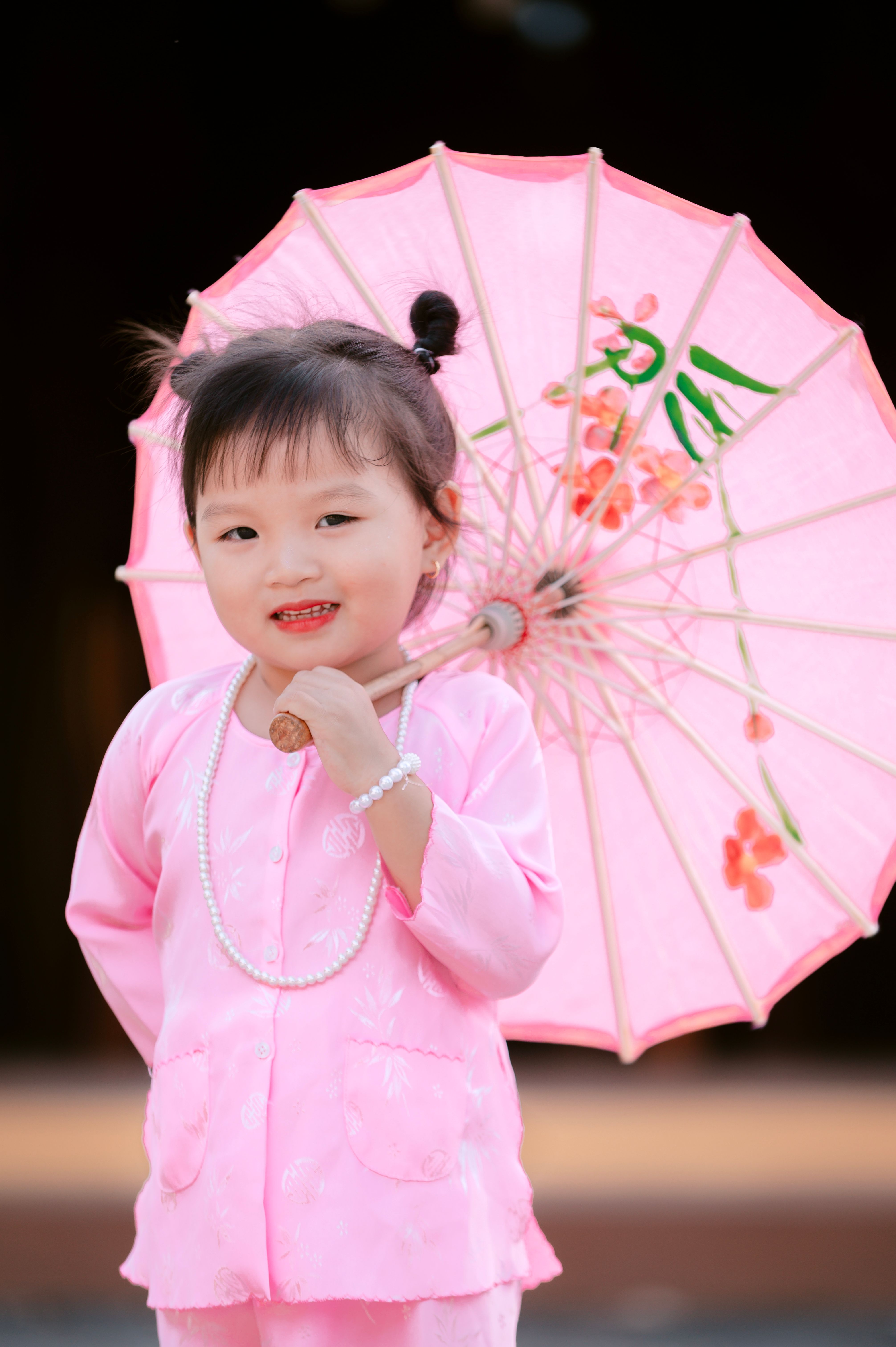 Charming Child in Traditional Pink Attire with Umbrella · Free Stock Photo