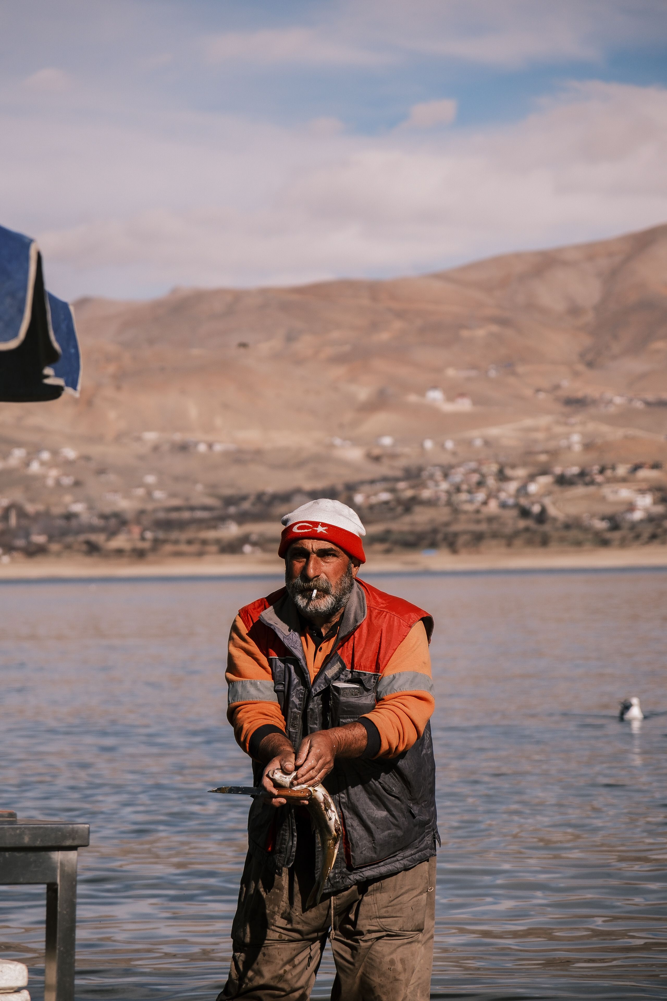 Fisherman by a Mountain Lake with Fish Catch · Free Stock Photo