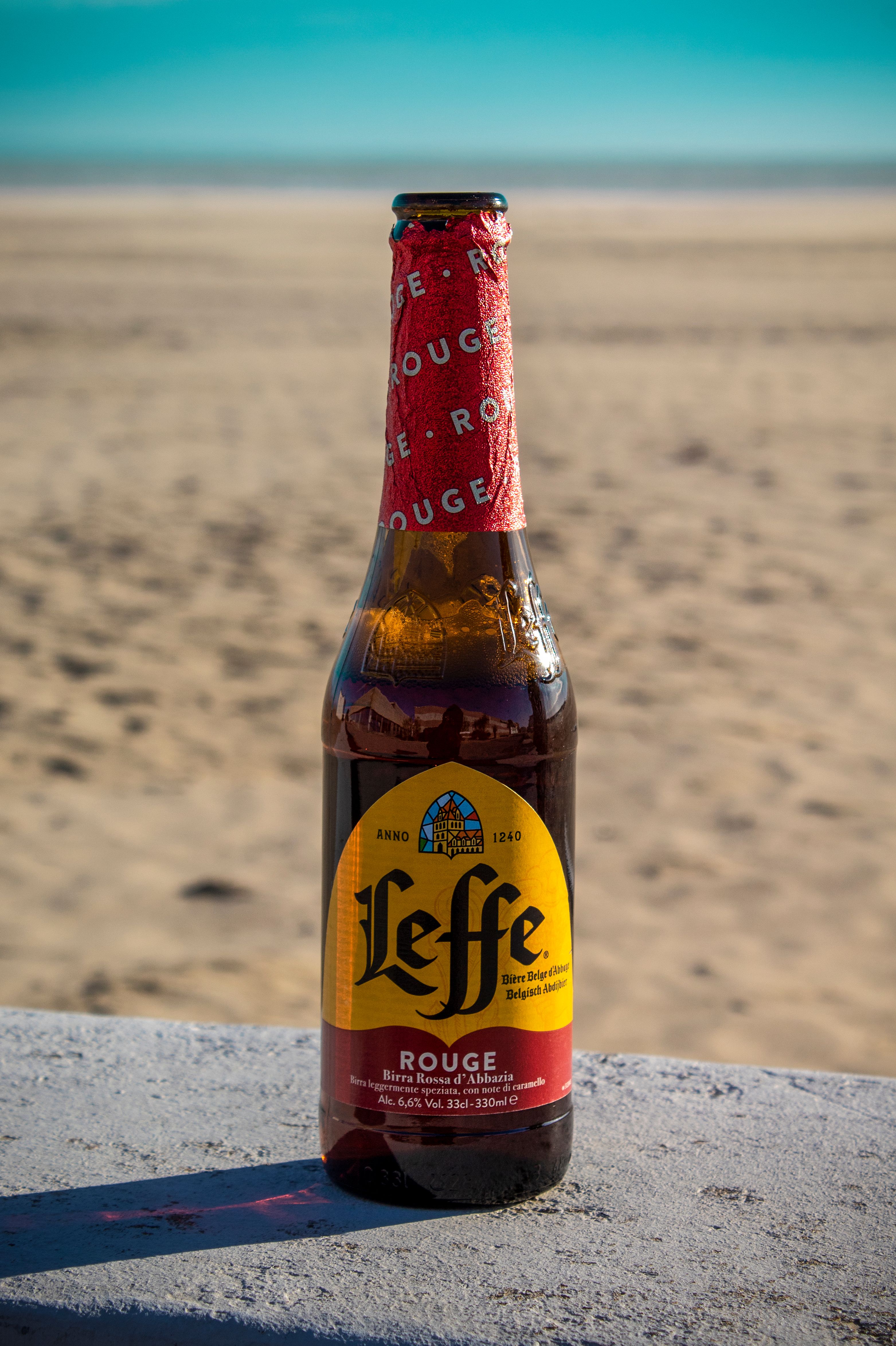 Leffe Rouge Beer Bottle on Sandy Beach · Free Stock Photo