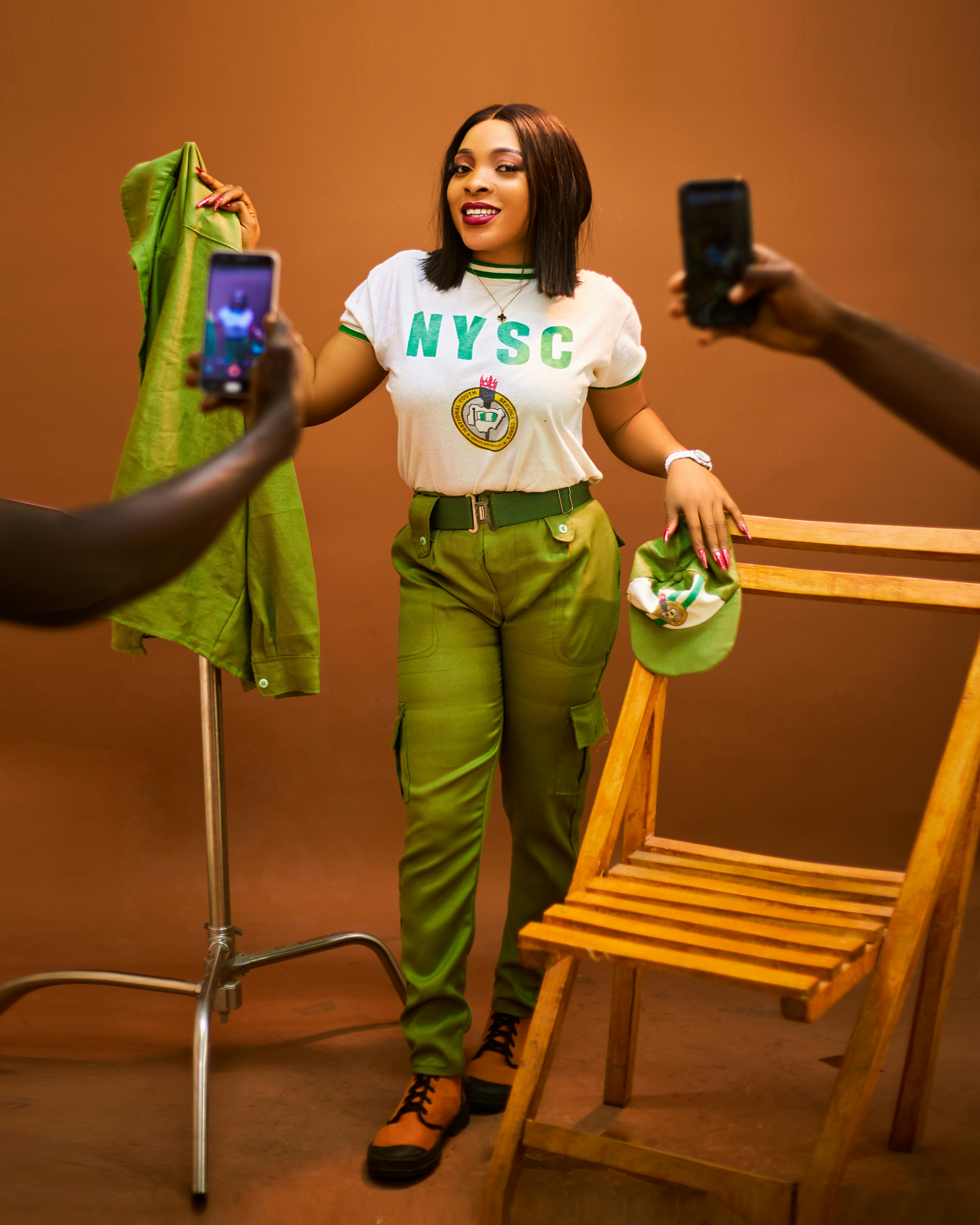 Young Adult in NYSC Uniform with Mobile Cameras · Free Stock Photo