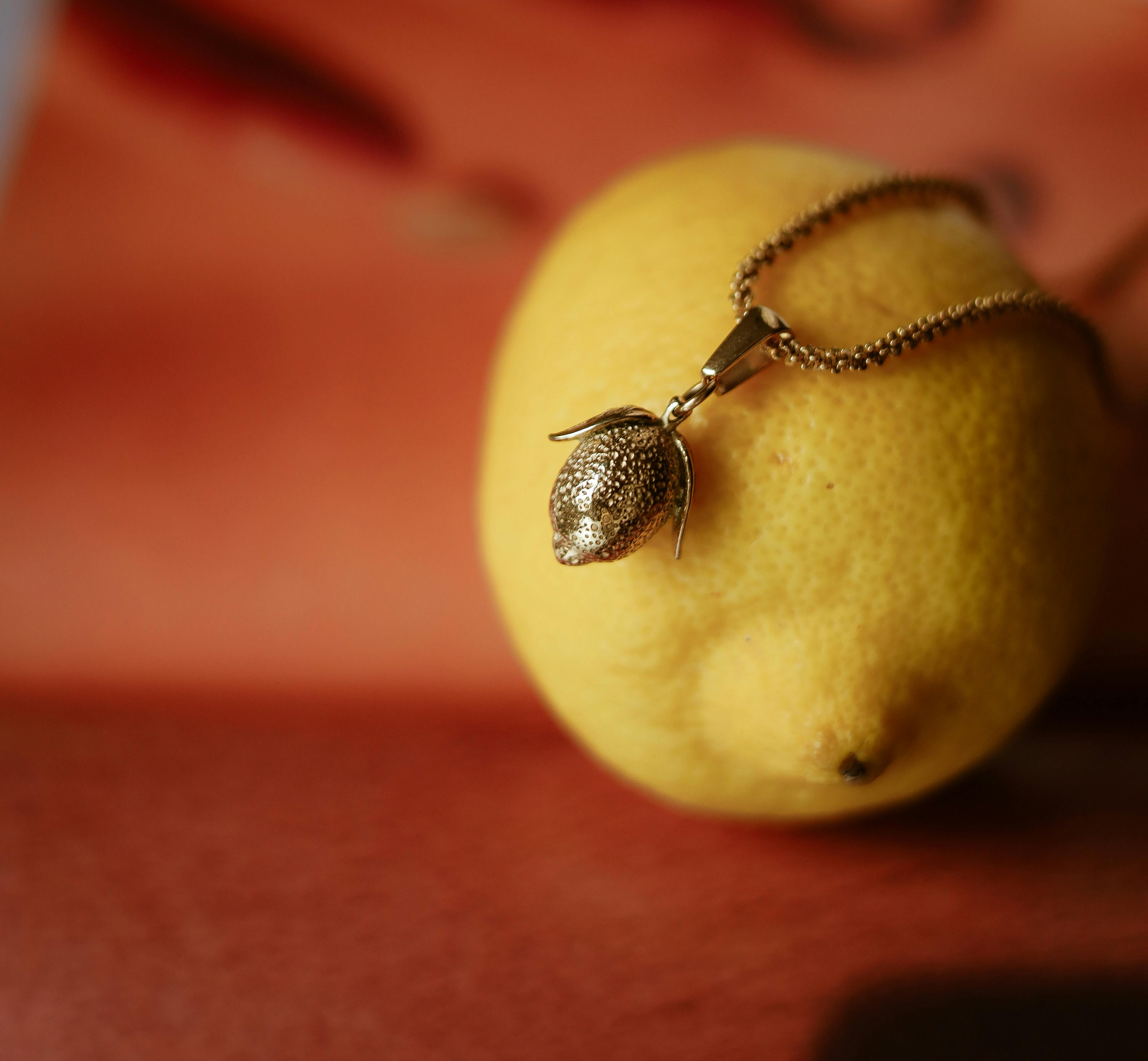 Golden Lemon Pendant on Lemon Fruit Close-Up · Free Stock Photo
