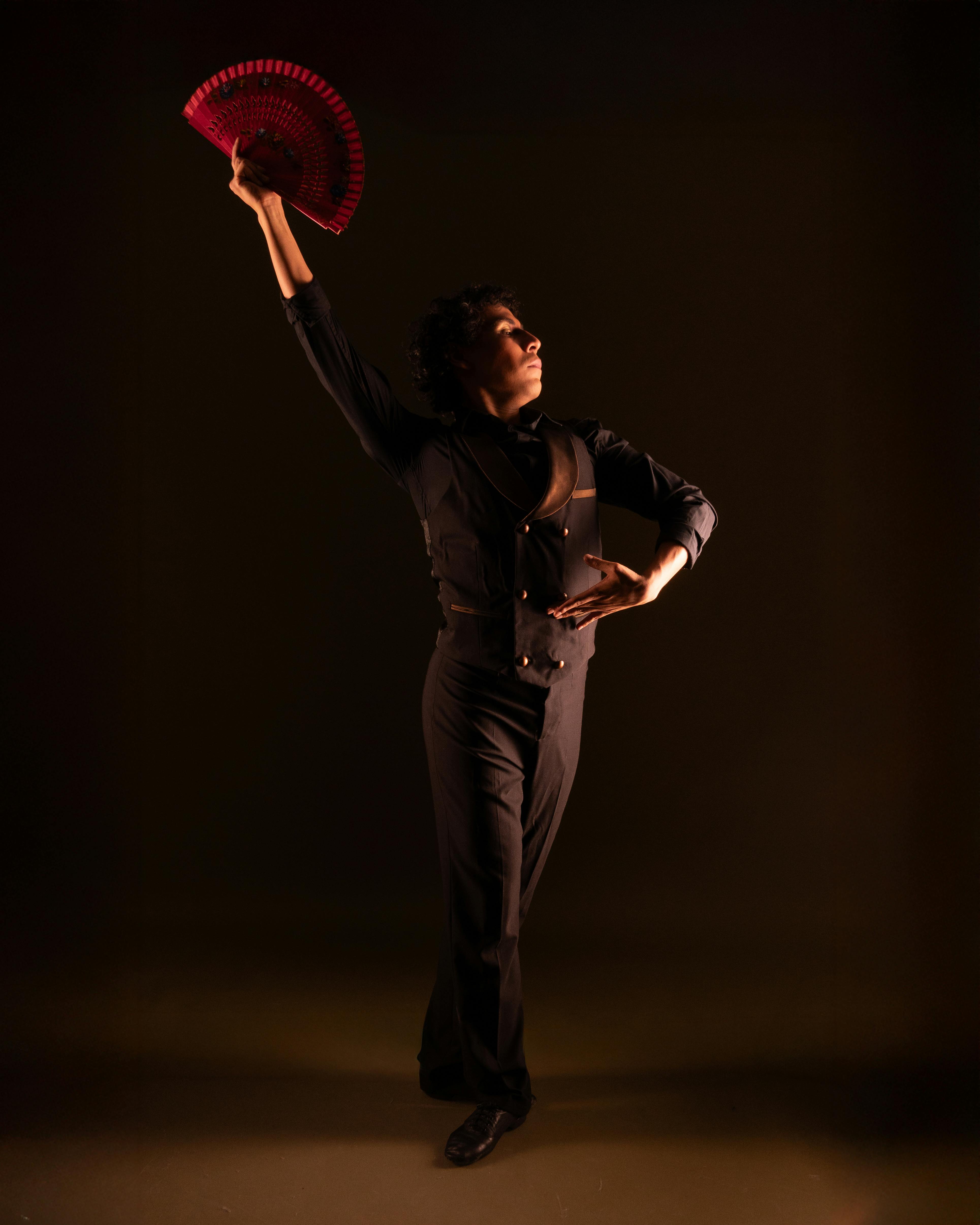 Expressive Male Dancer with Fan in Dramatic Lighting · Free Stock Photo