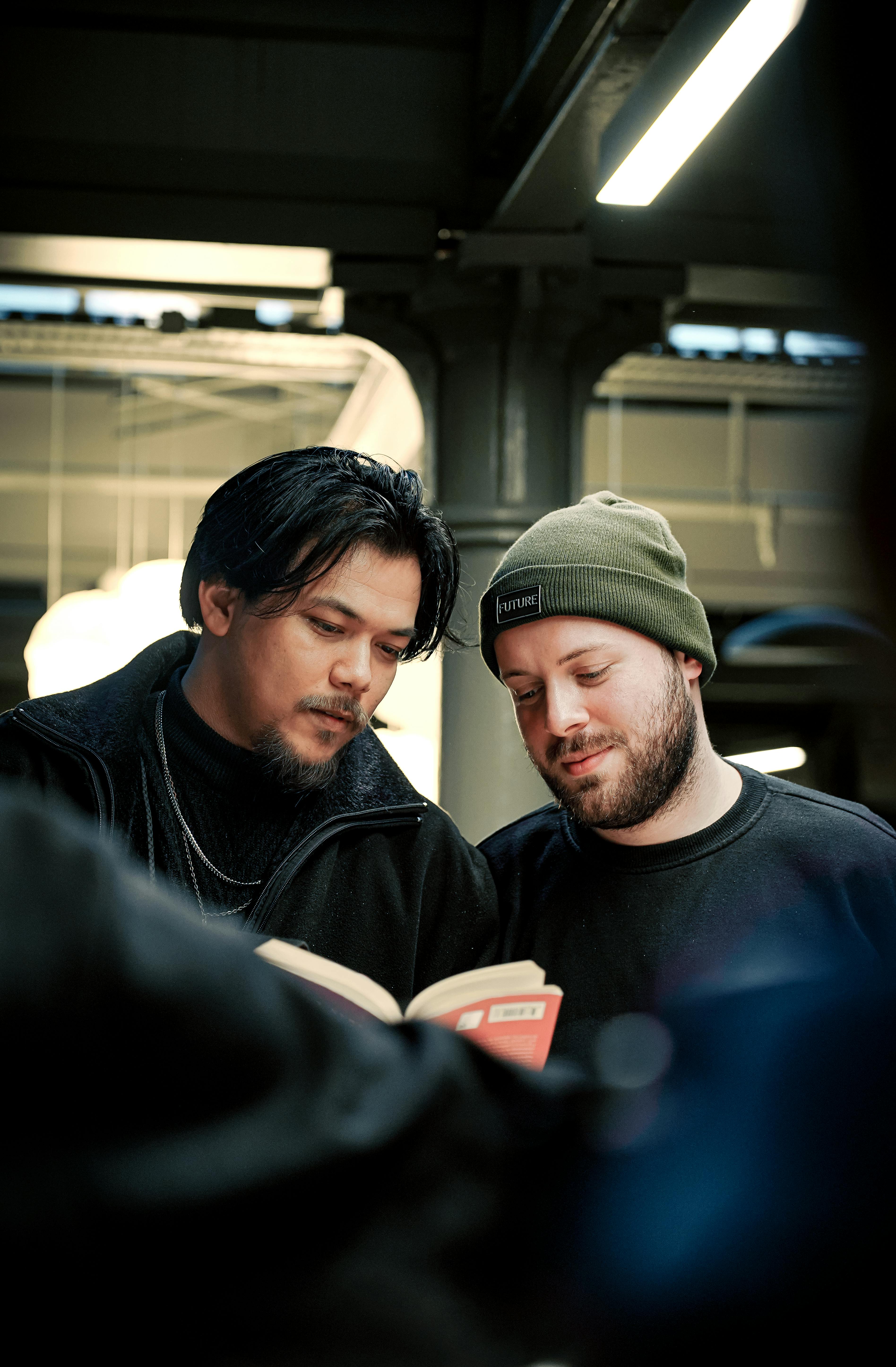 Two Men Reading a Book in an Indoor Setting · Free Stock Photo