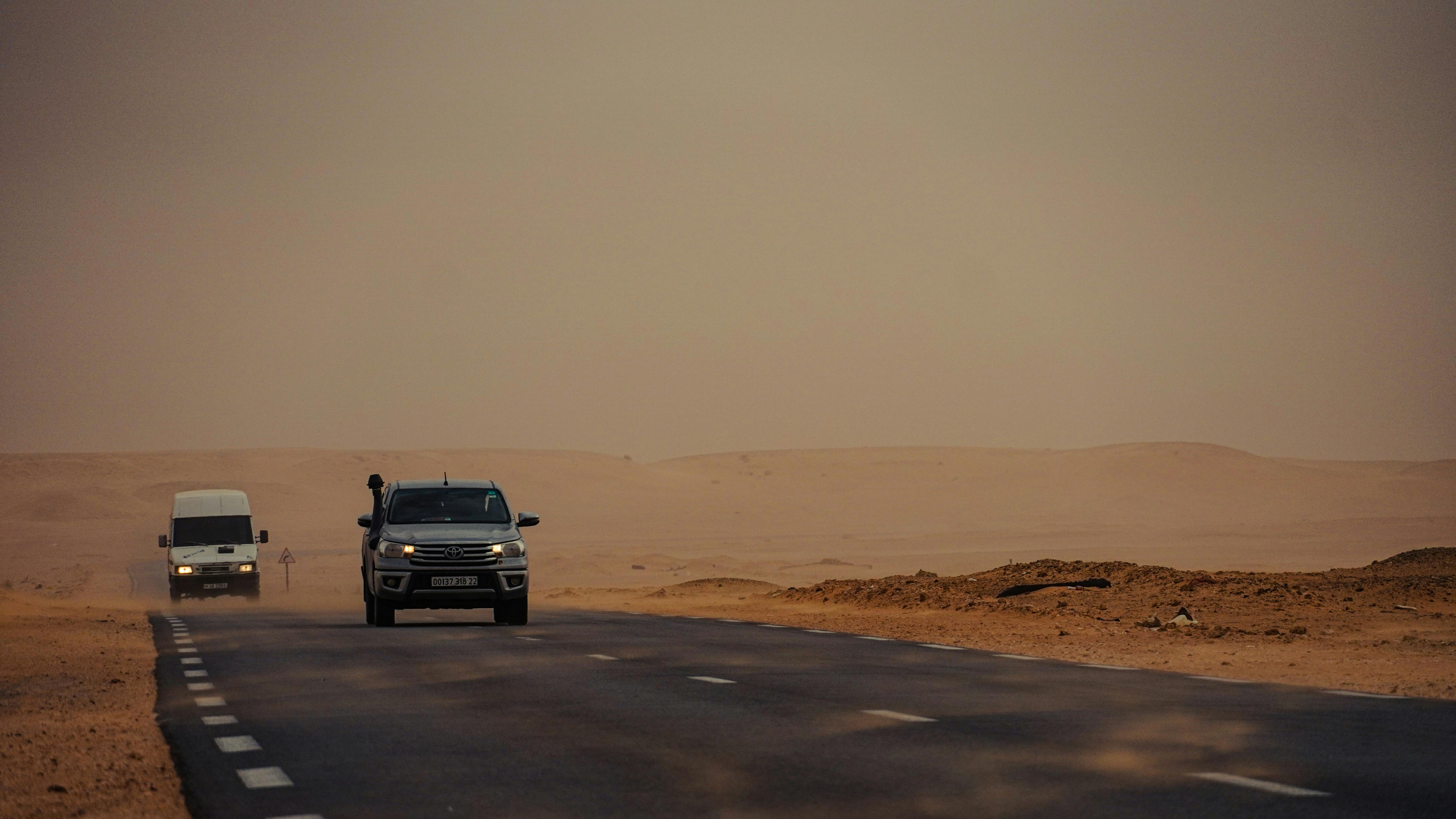 Cars driving through the desert on a long road · Free Stock Photo