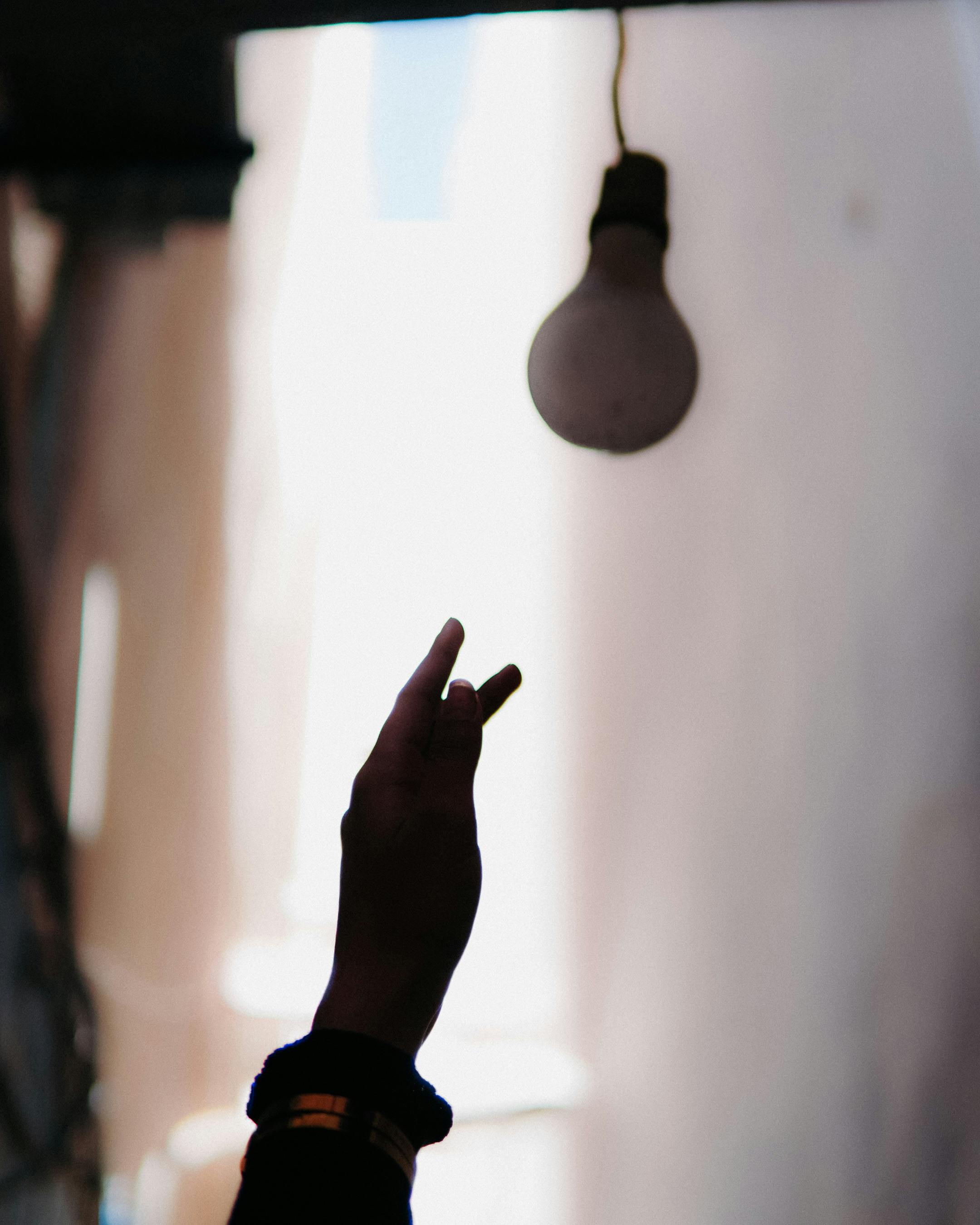 Woman About To Hold A Pendant Lamp · Free Stock Photo