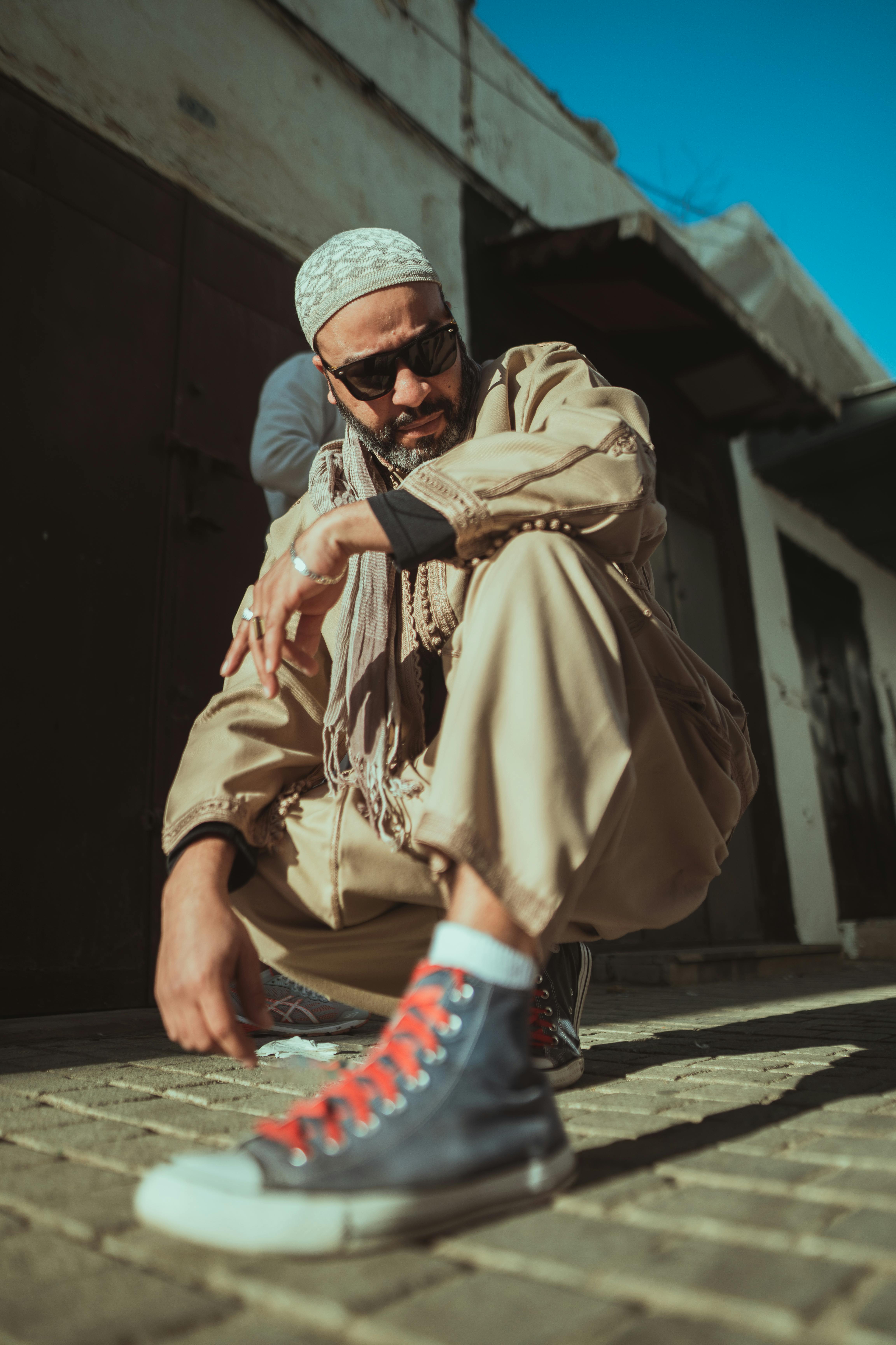 Stylish man in sunglasses crouching outdoors · Free Stock Photo