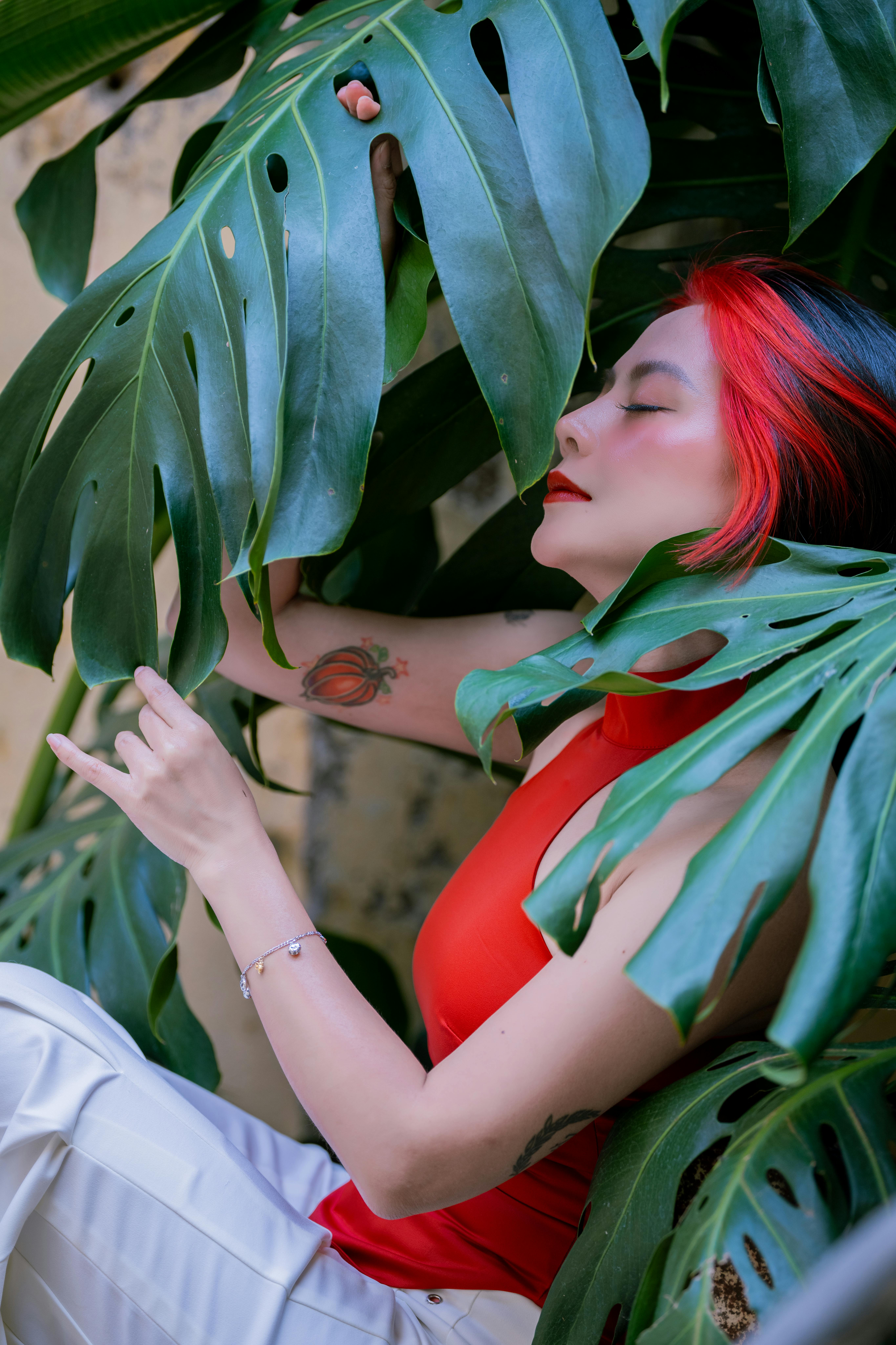 Contemplative Woman Amidst Green Foliage · Free Stock Photo