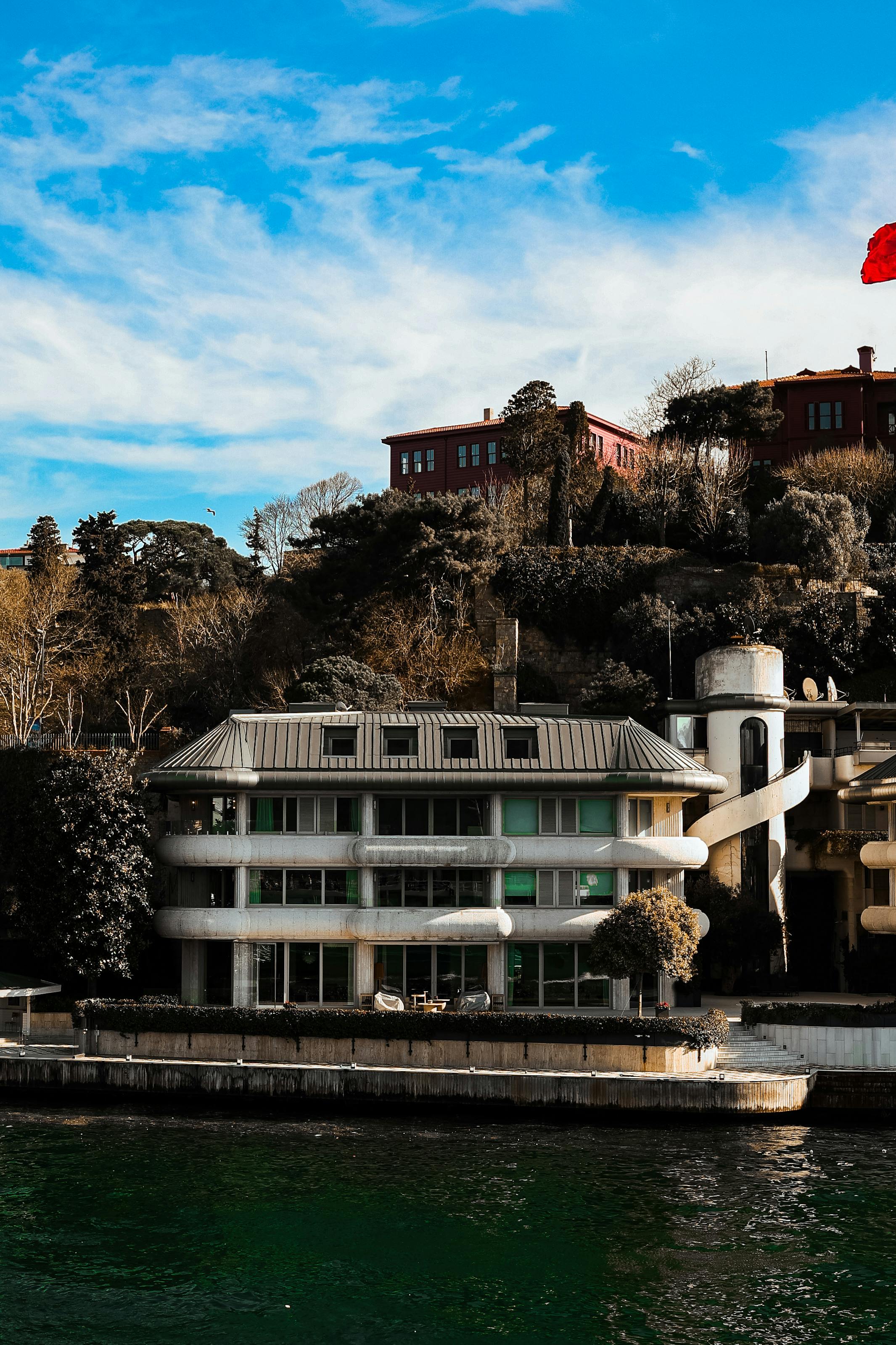 Modern Riverside House and Red Roofed Buildings · Free Stock Photo