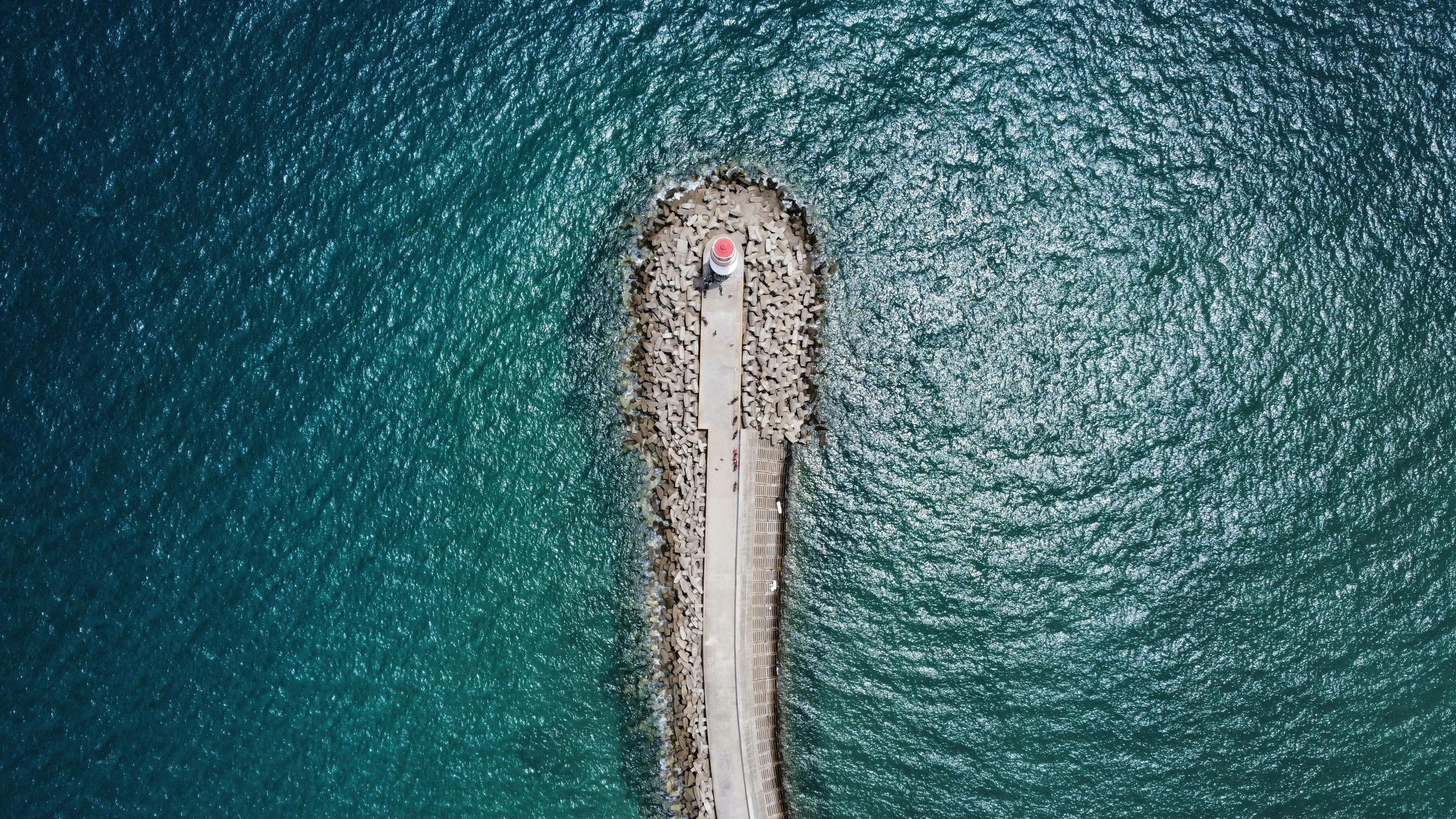 Aerial View of a Lighthouse Jetty Over Pristine Waters · Free Stock Photo