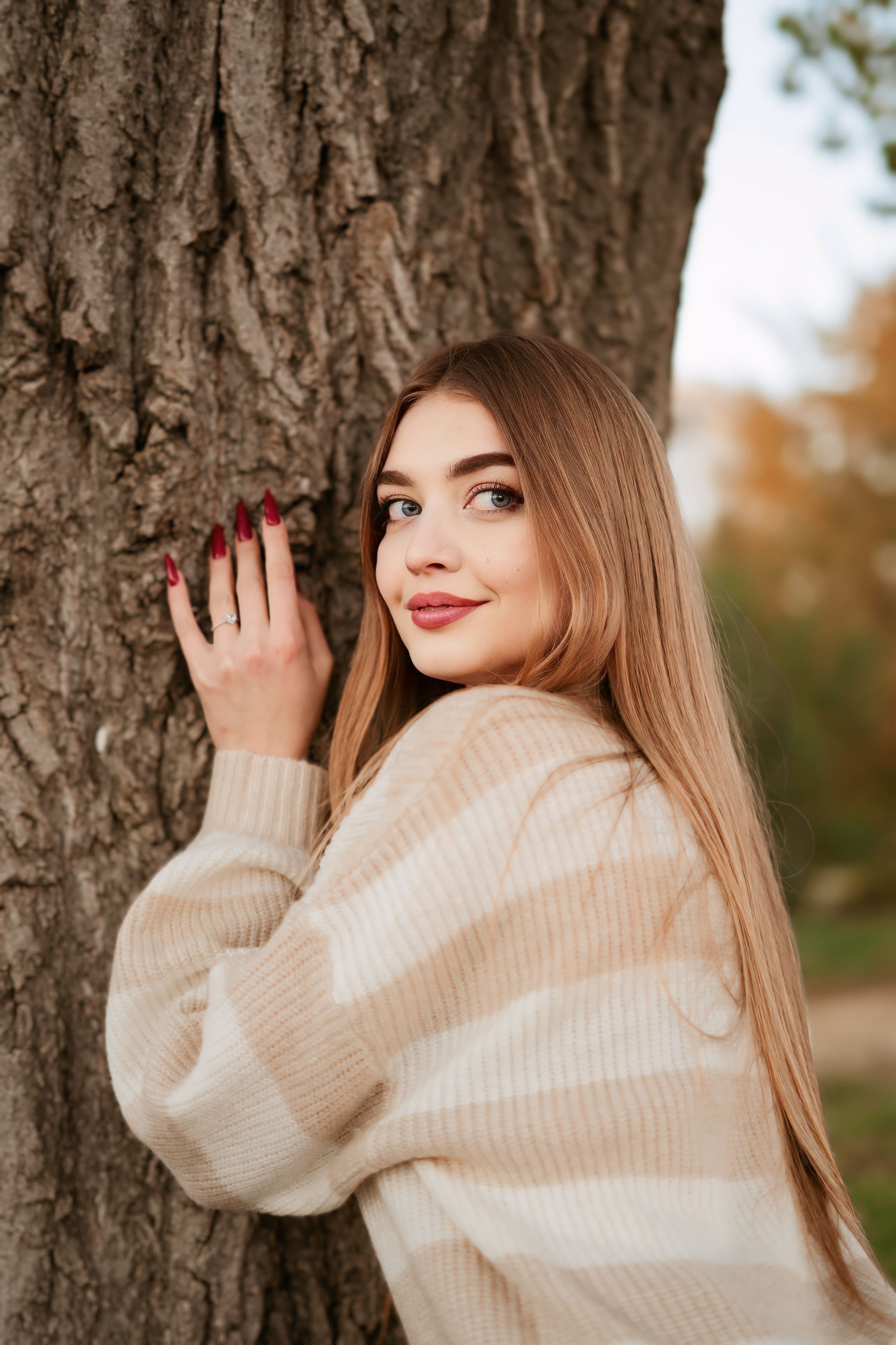 Woman with long hair leaning against a tree · Free Stock Photo