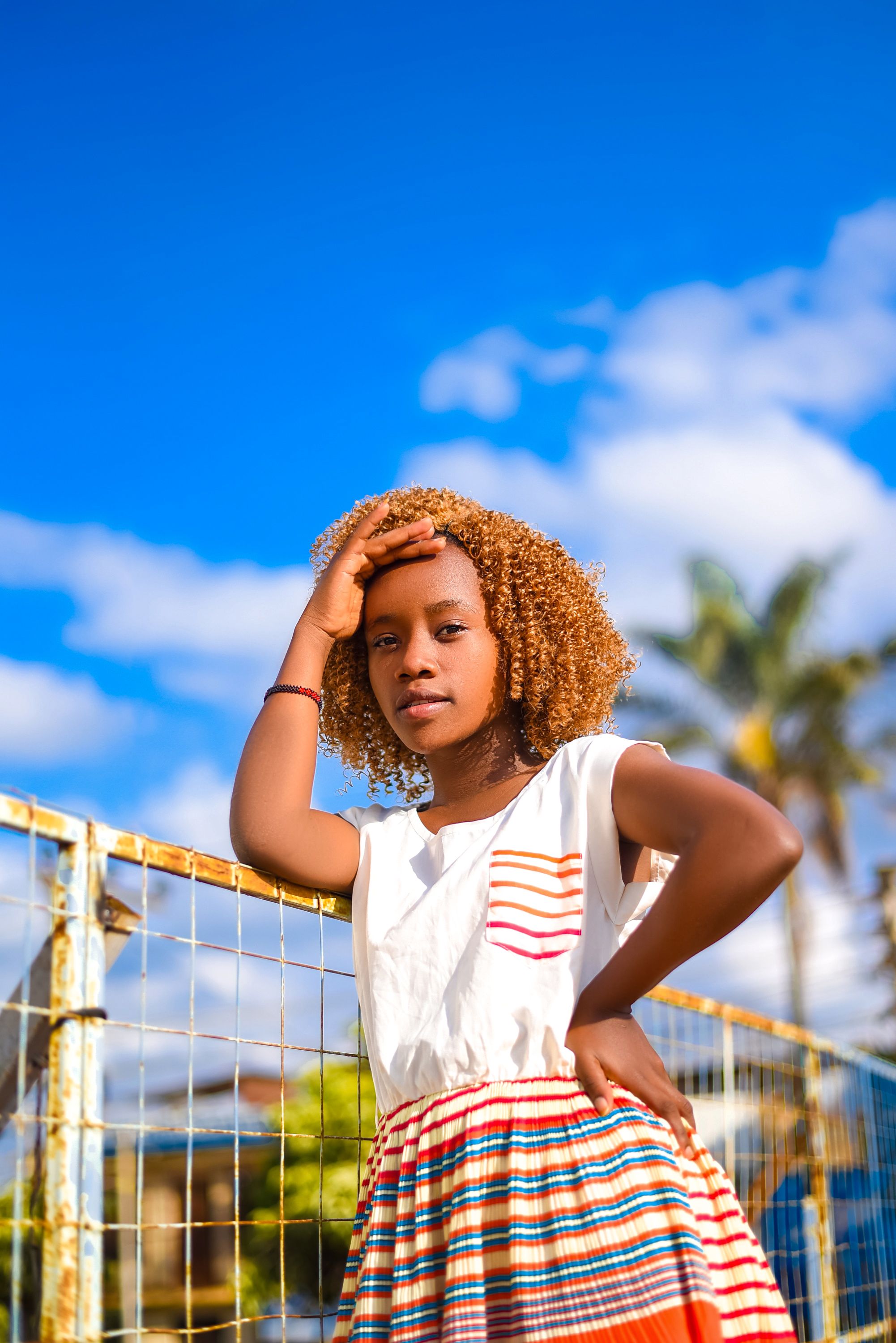 Young Girl Posing Outdoors Against Blue Sky · Free Stock Photo