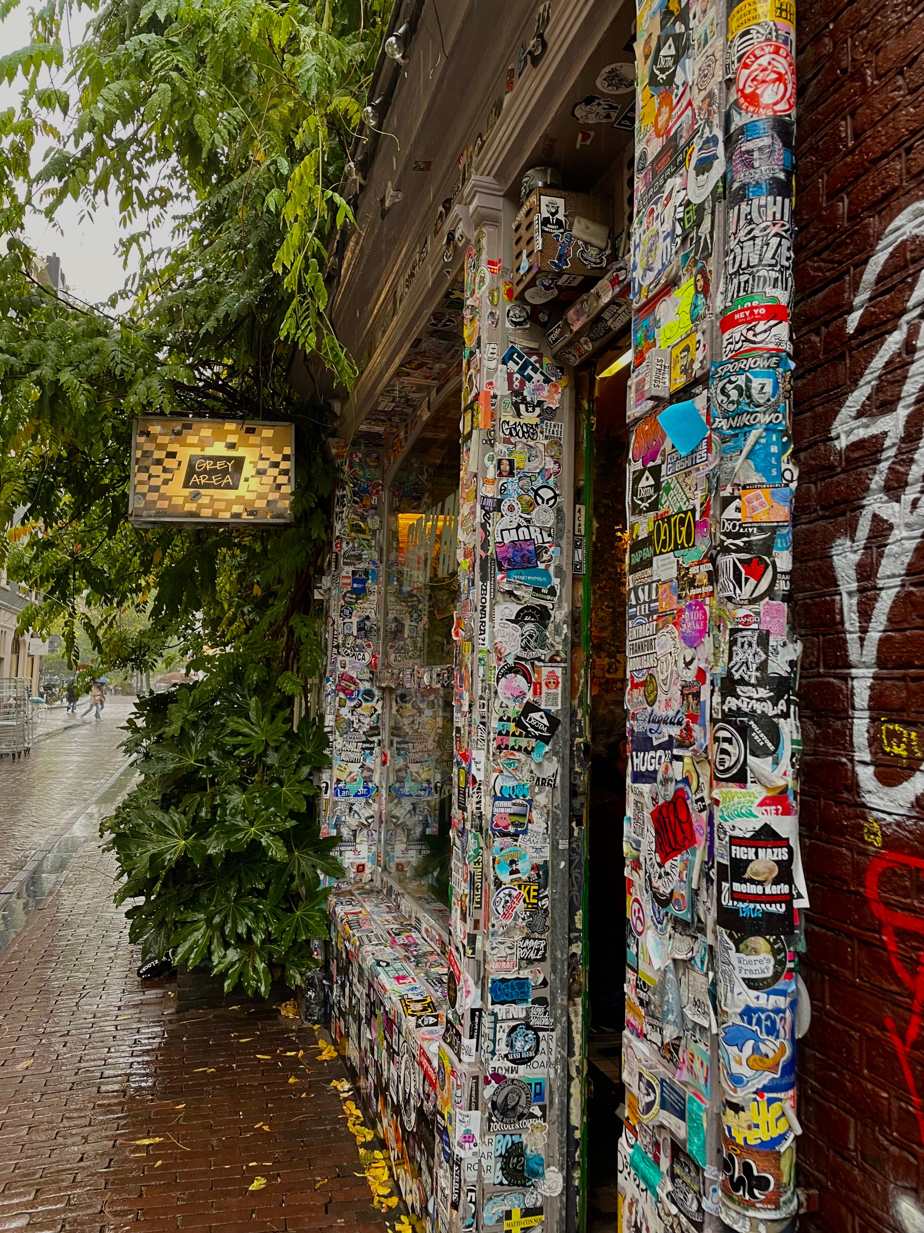 Colorful Sticker Covered Shopfront in Rainy Amsterdam · Free Stock Photo