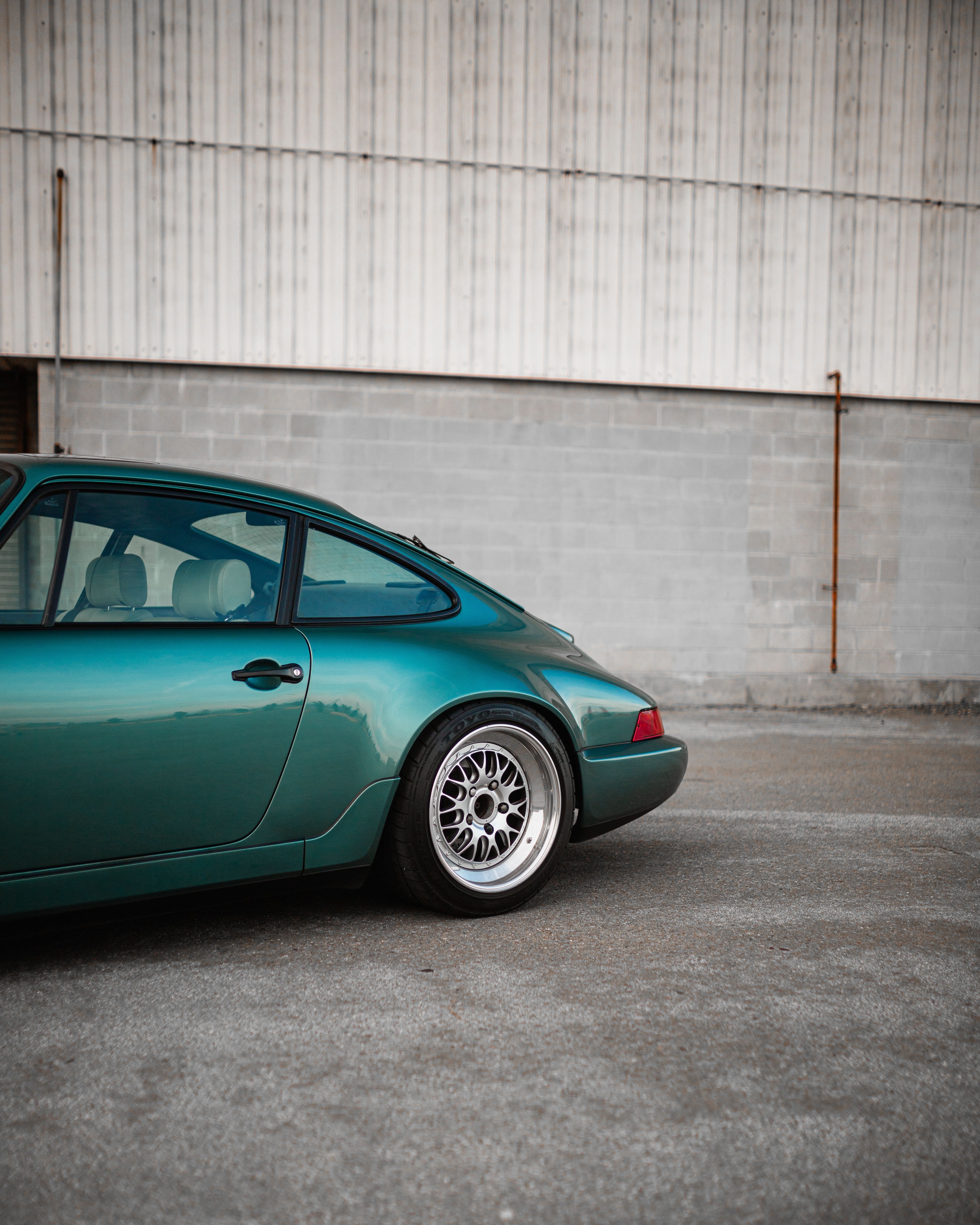 Vintage teal sports car in industrial setting · Free Stock Photo