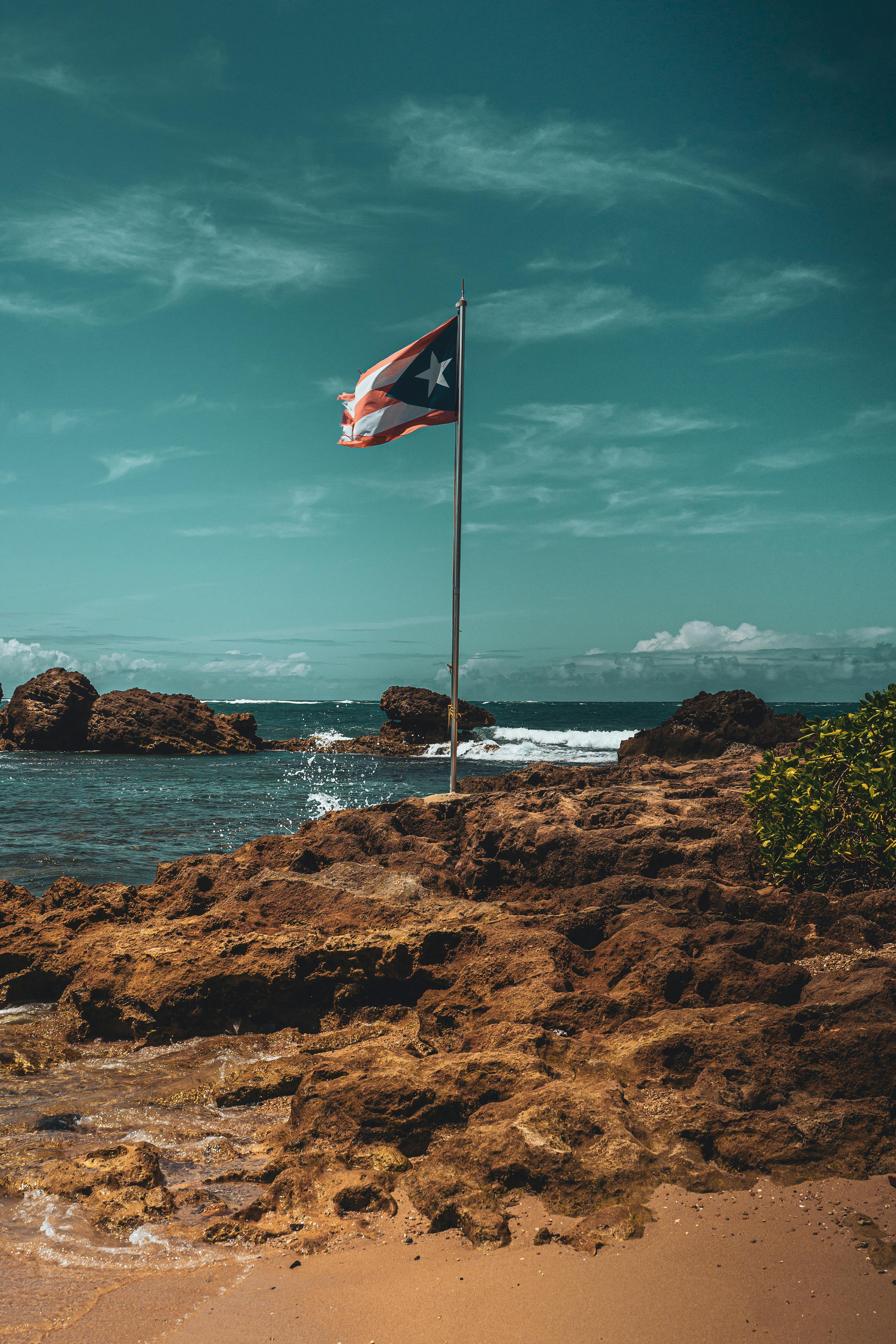 Puerto Rican Flag on Coastal Rocks in San Juan · Free Stock Photo