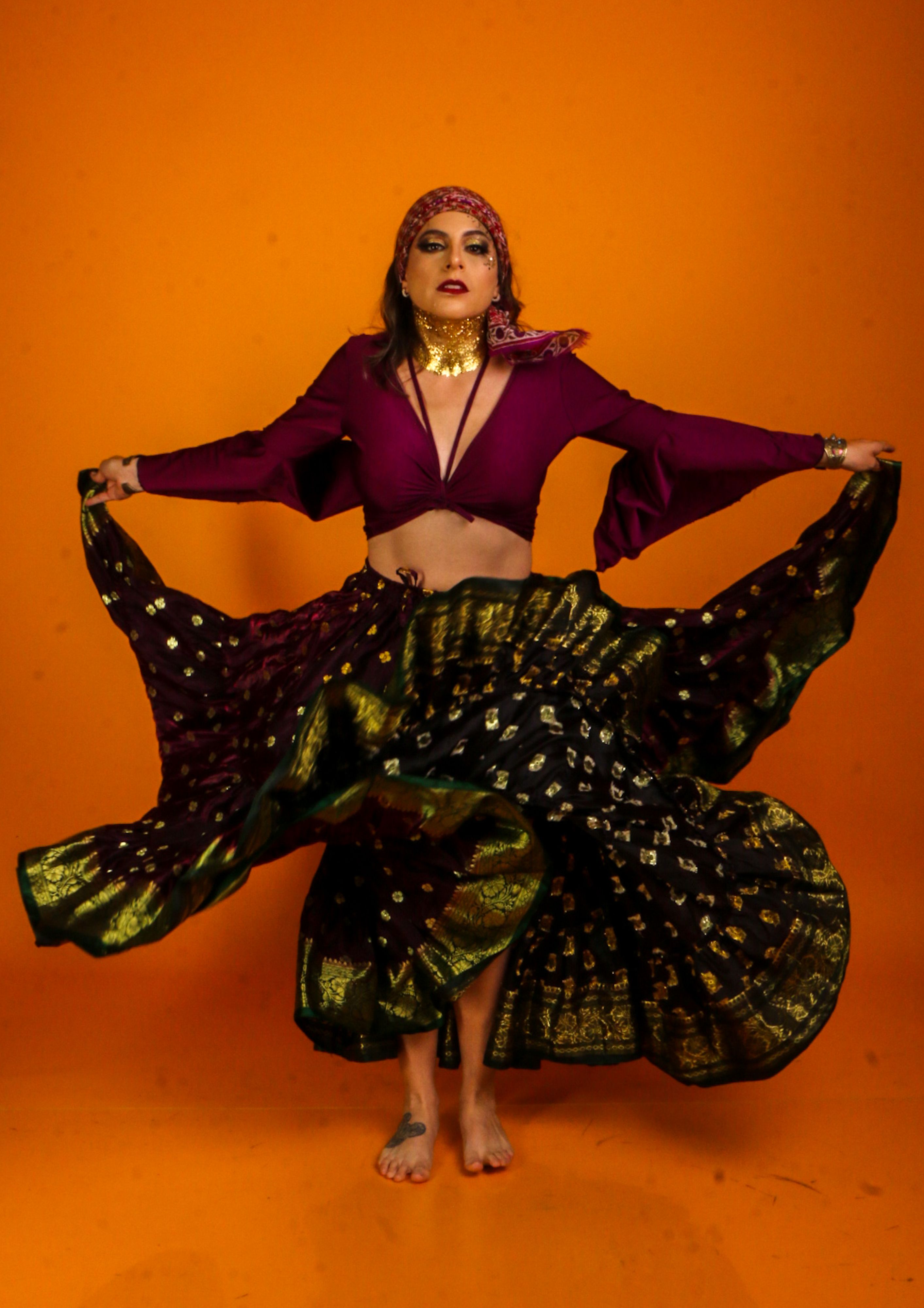 Vibrant Traditional Dance Pose on Orange Background · Free Stock Photo