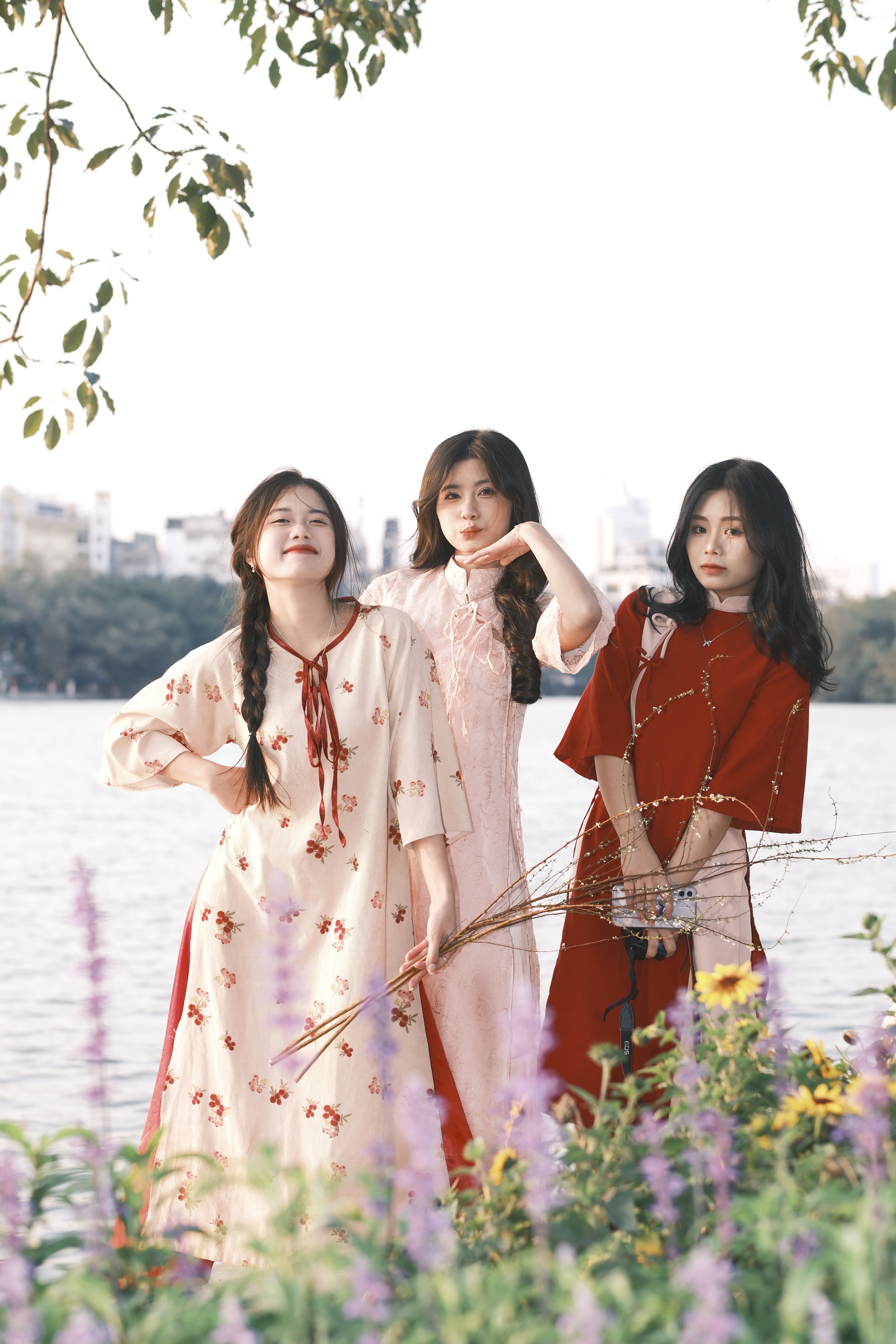 Three women in traditional dresses by a serene lake · Free Stock Photo