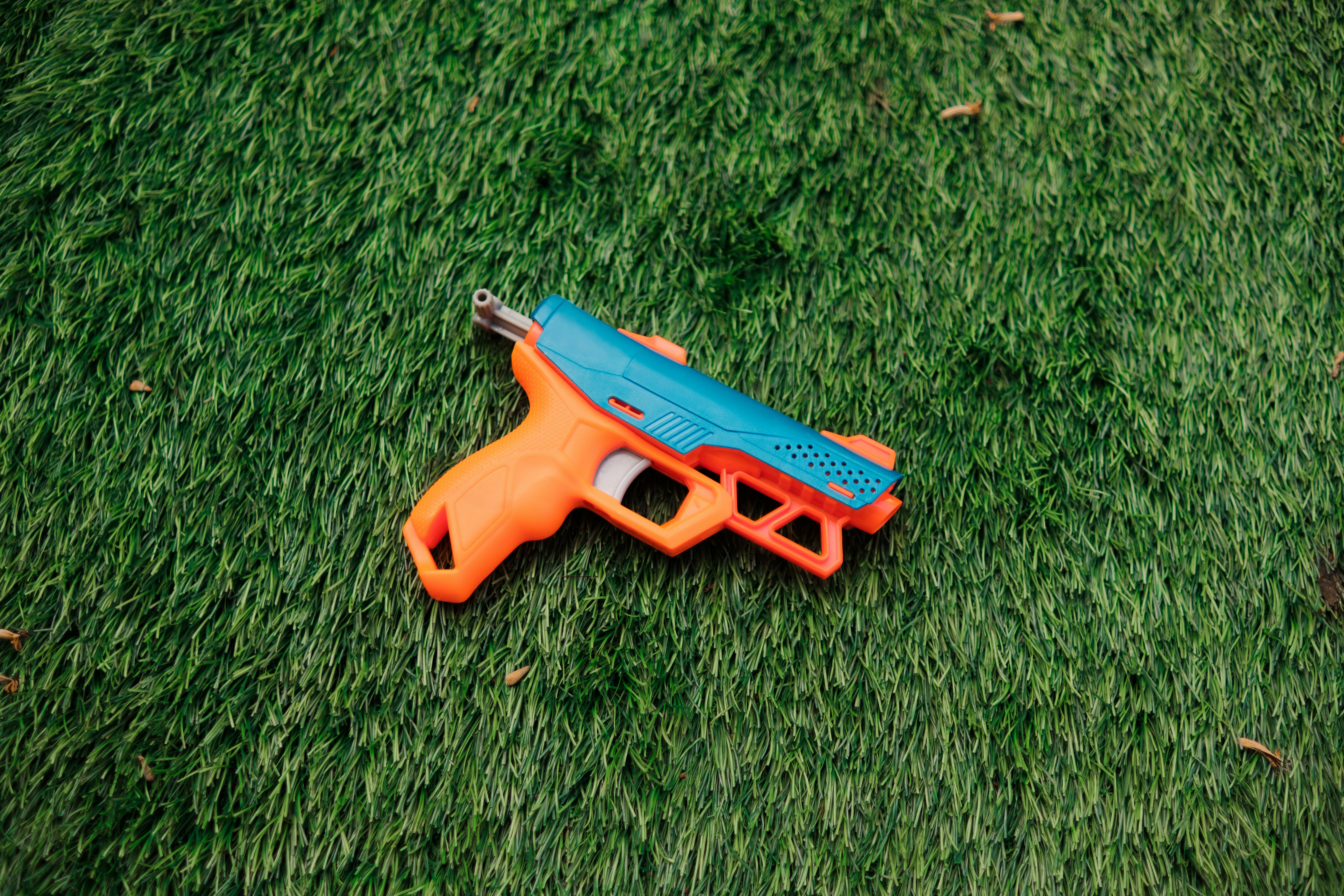 Colorful Toy Gun on Green Grass Outdoors · Free Stock Photo