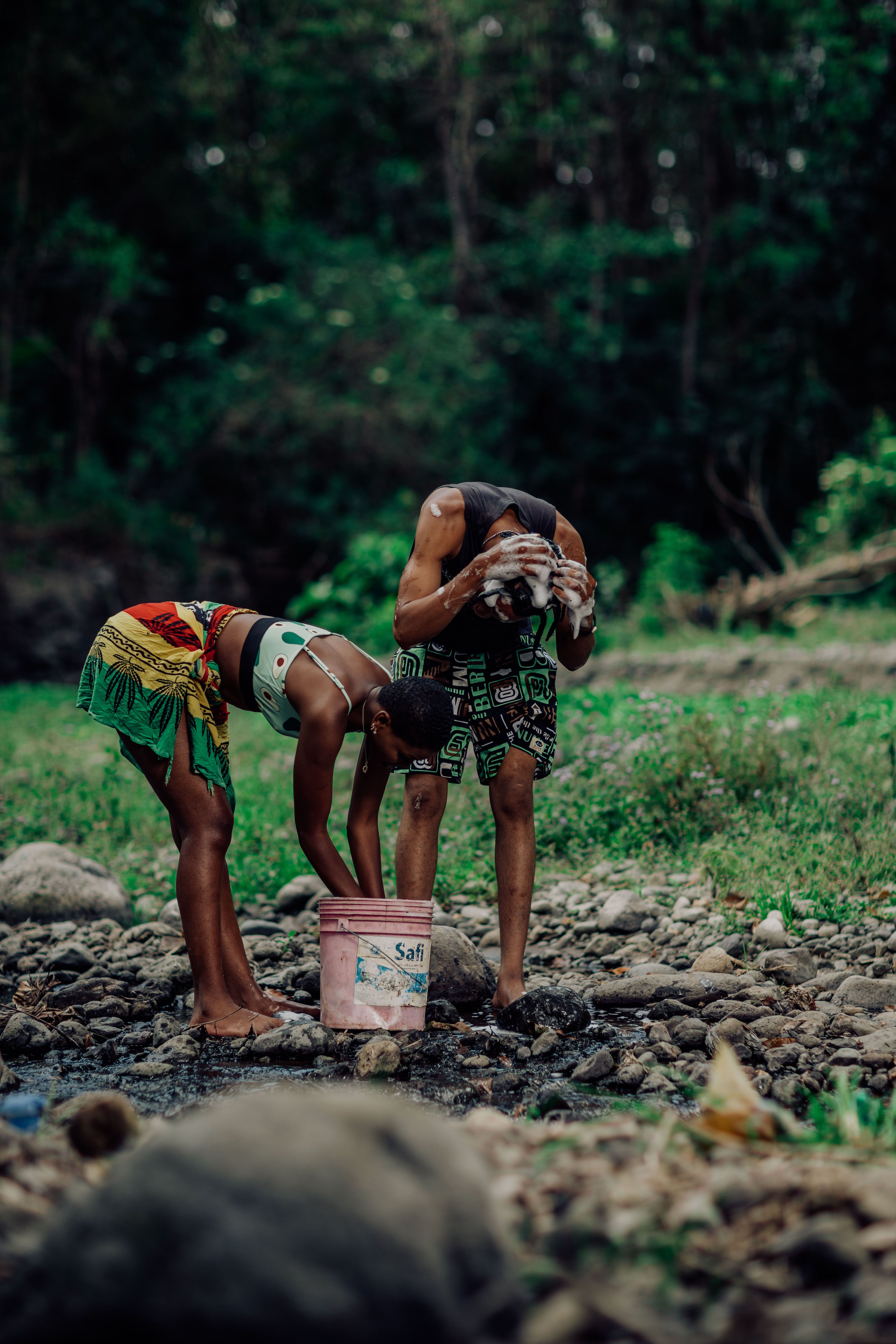 People Washing by Stream in Lush Forest Setting · Free Stock Photo