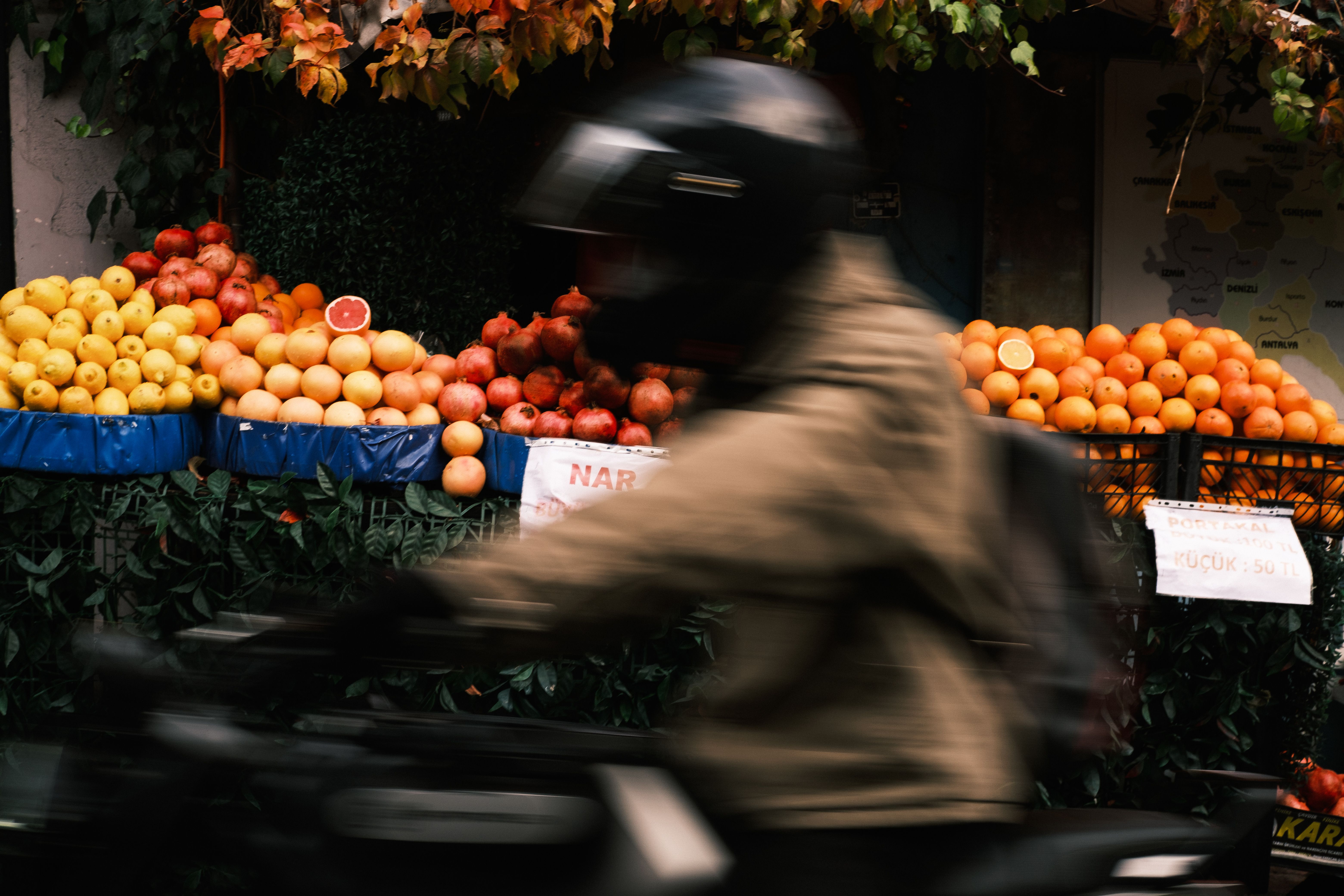 Blurred Motorcyclist Passing Colorful Fruit Stand · Free Stock Photo