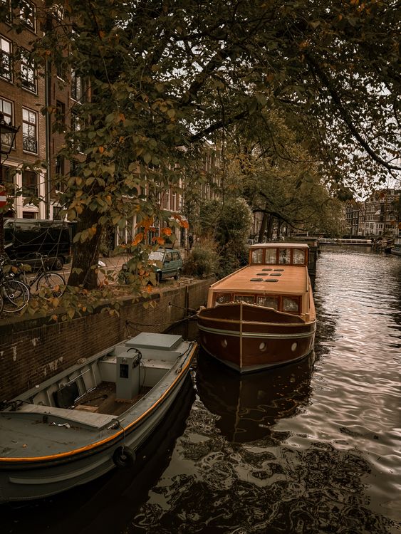 Amsterdam canal with boats moored alongside historic buildings in autumn