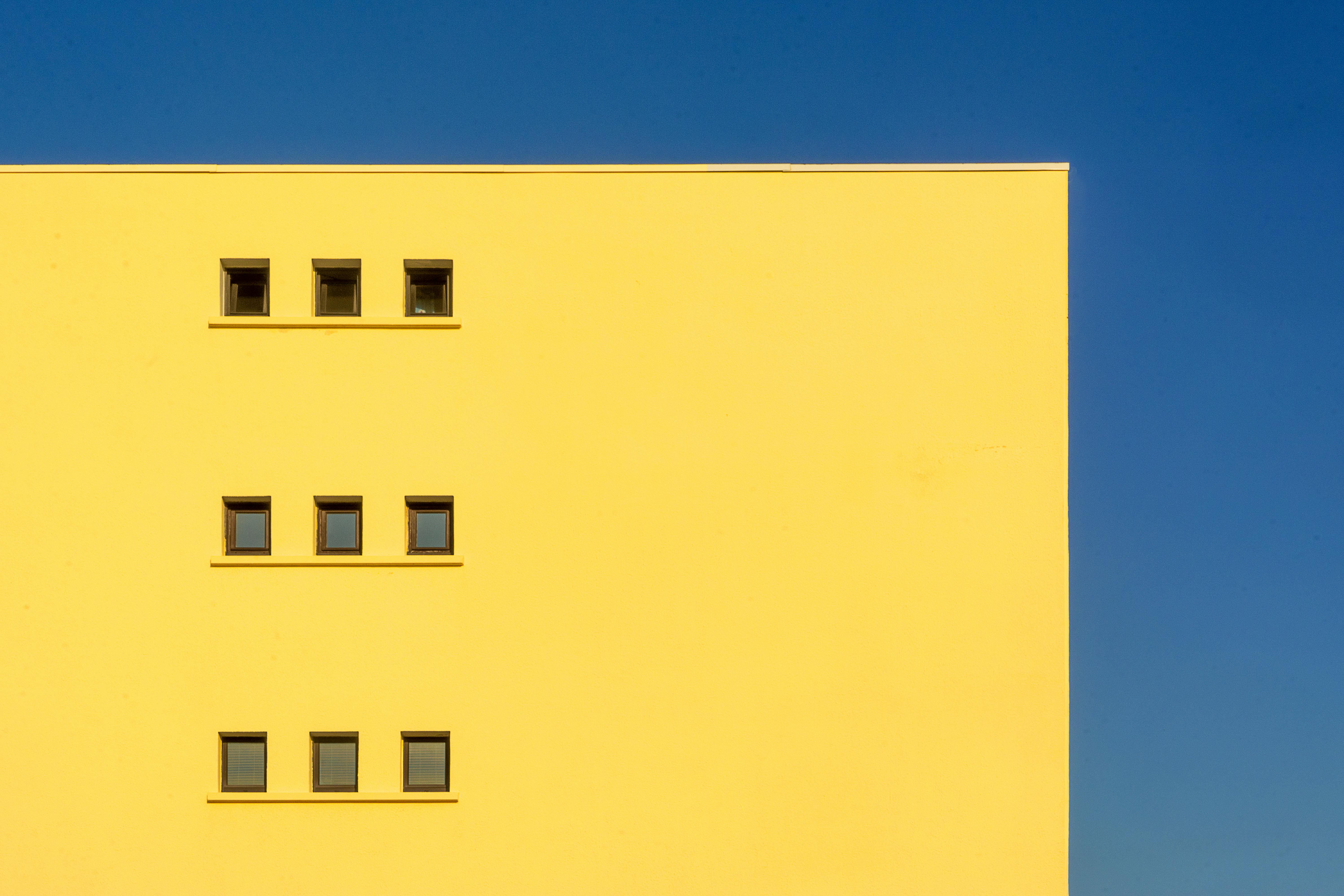 Modern Yellow Building Facade Against Clear Blue Sky · Free Stock Photo