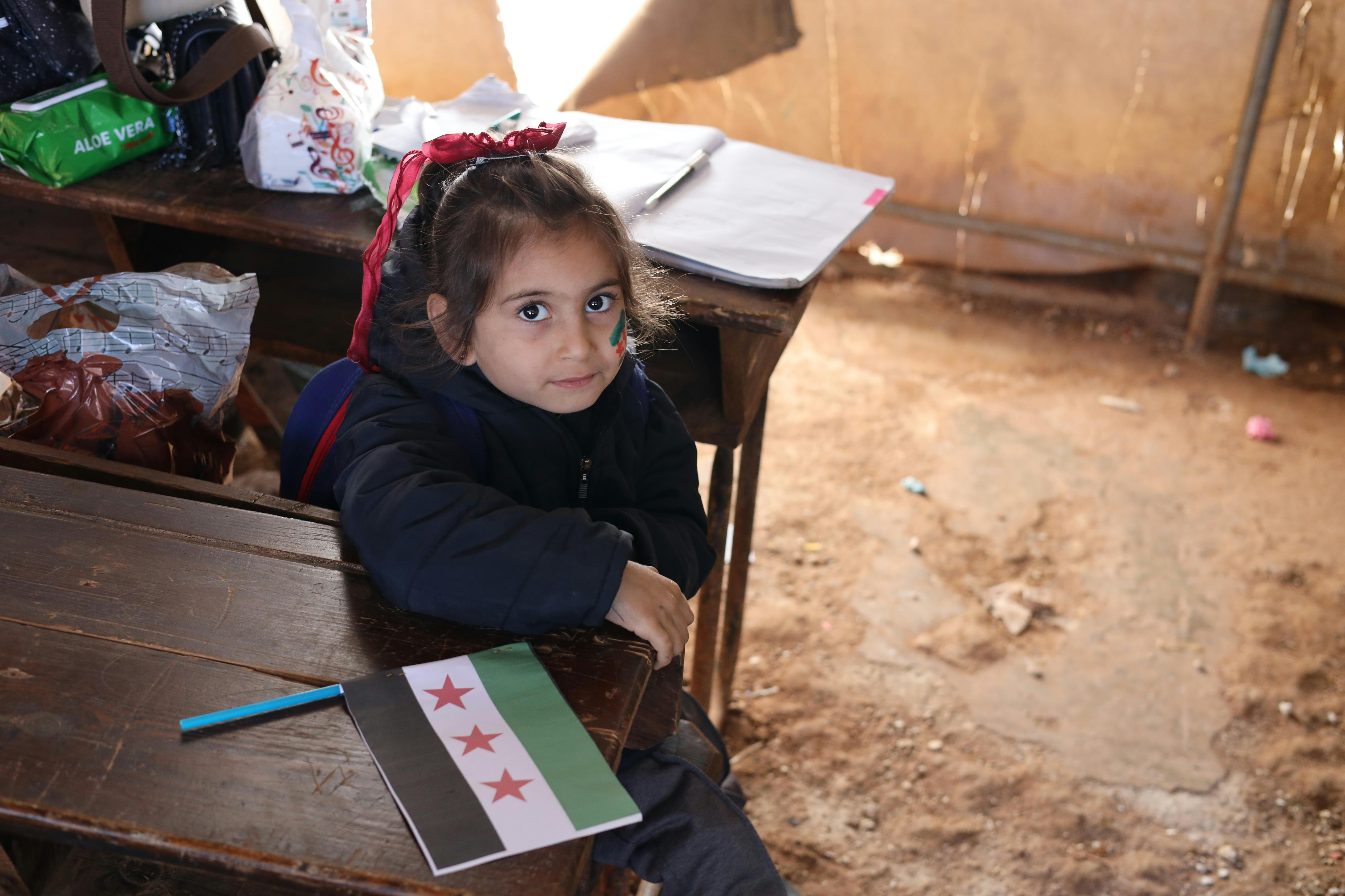 Young girl in Syrian classroom with flag · Free Stock Photo