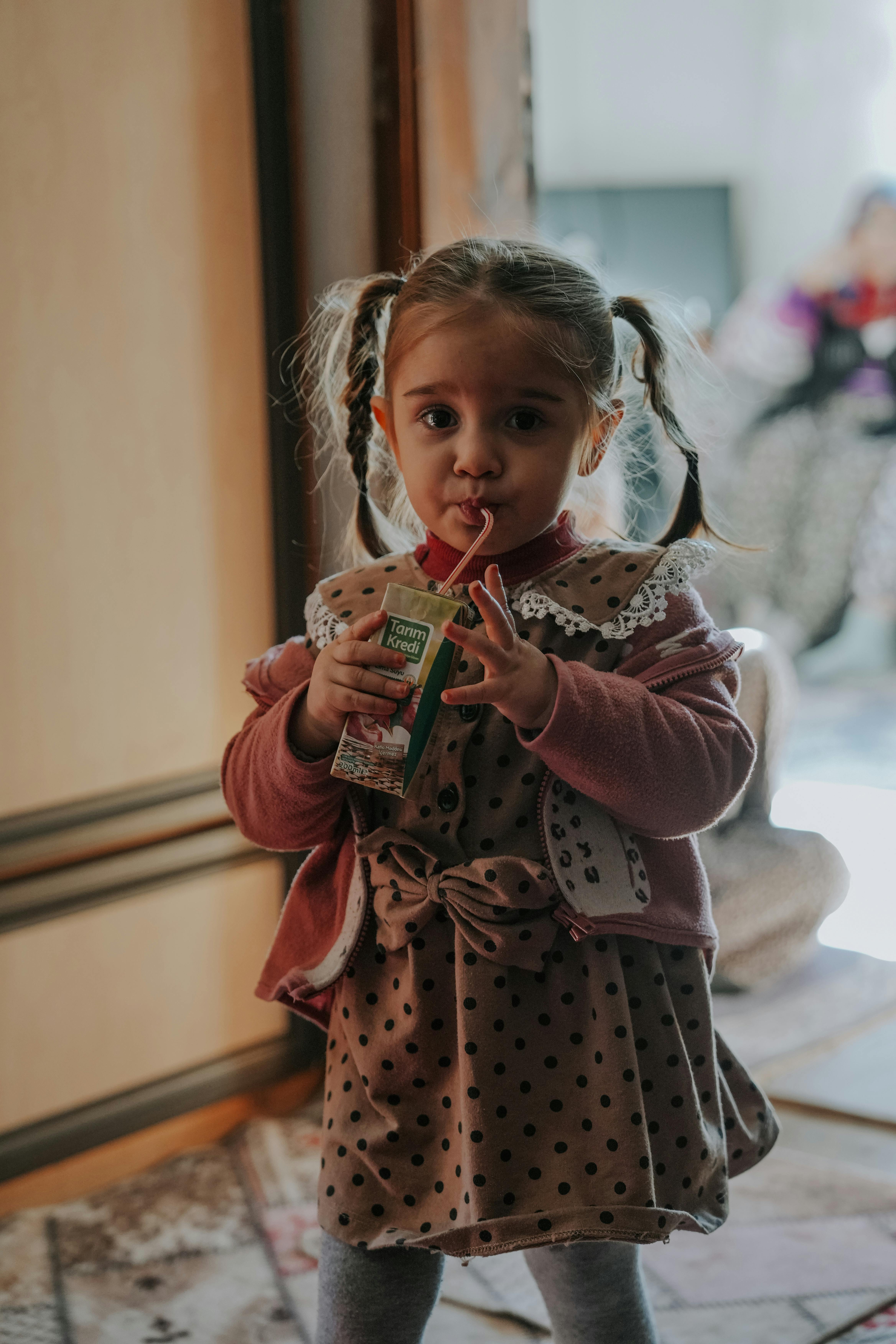 Adorable Child Sipping Juice Box Indoors · Free Stock Photo
