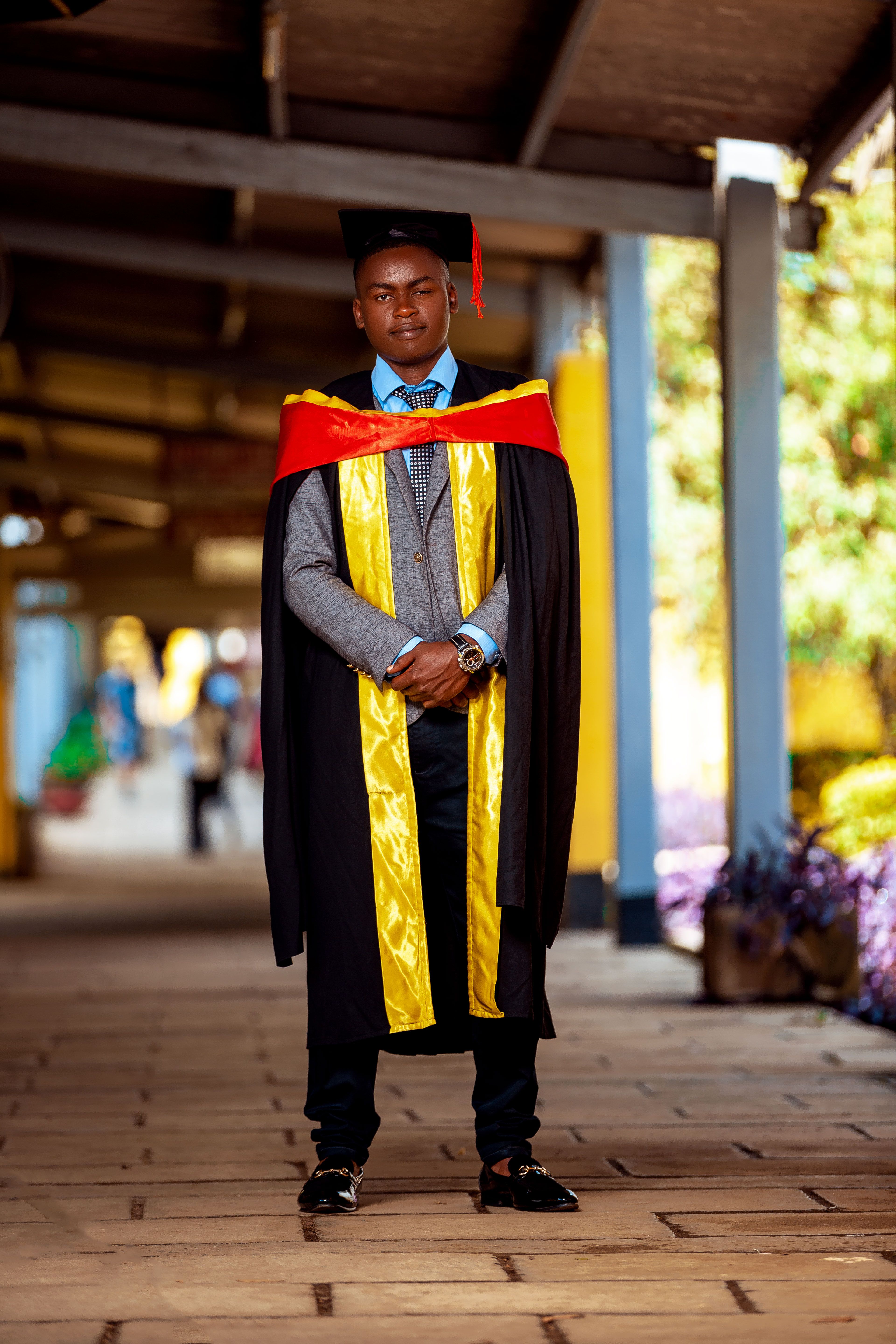 Young Man in Graduation Gown Standing Proudly · Free Stock Photo