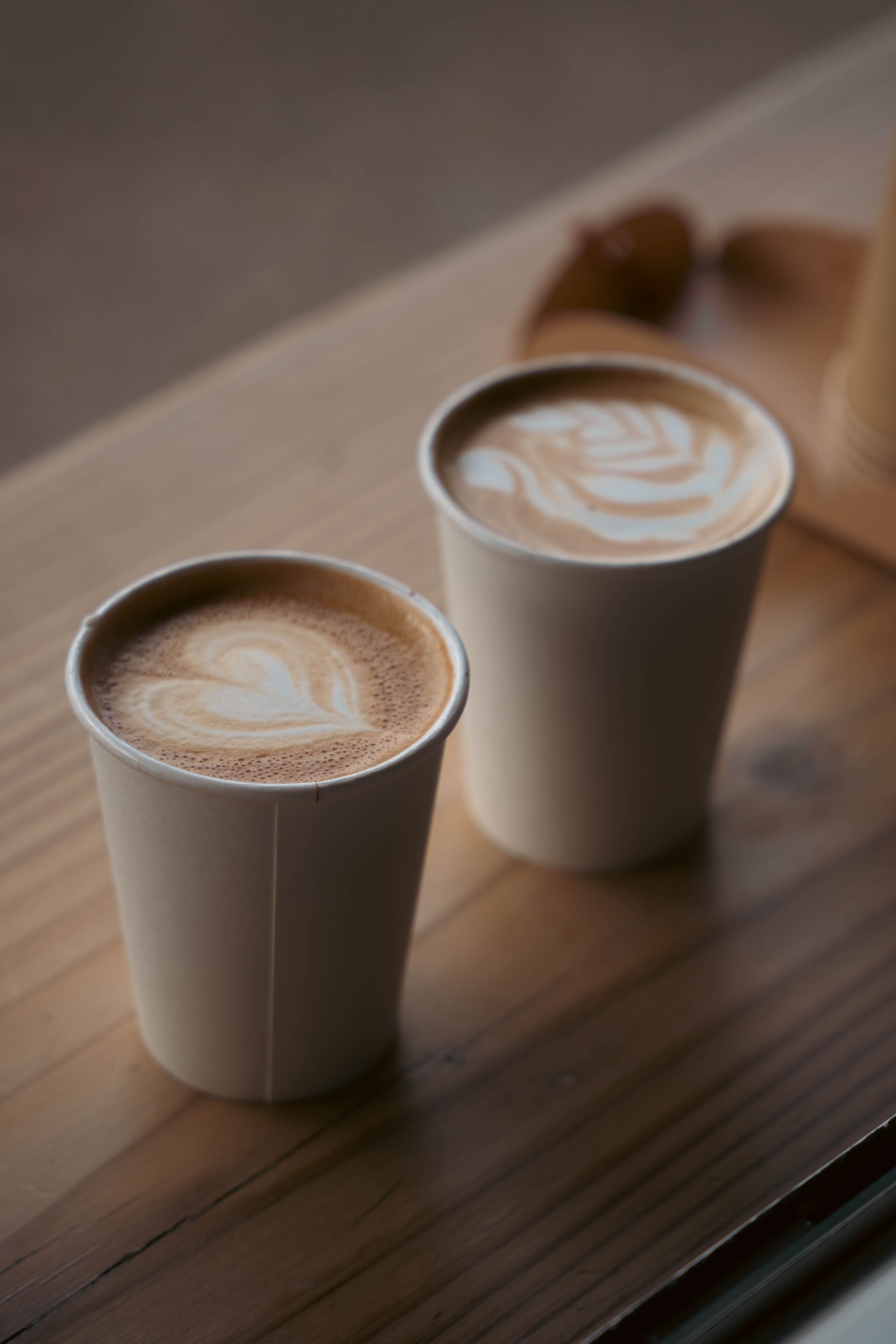 Two Artisan Lattes in Paper Cups on Wooden Table · Free Stock Photo