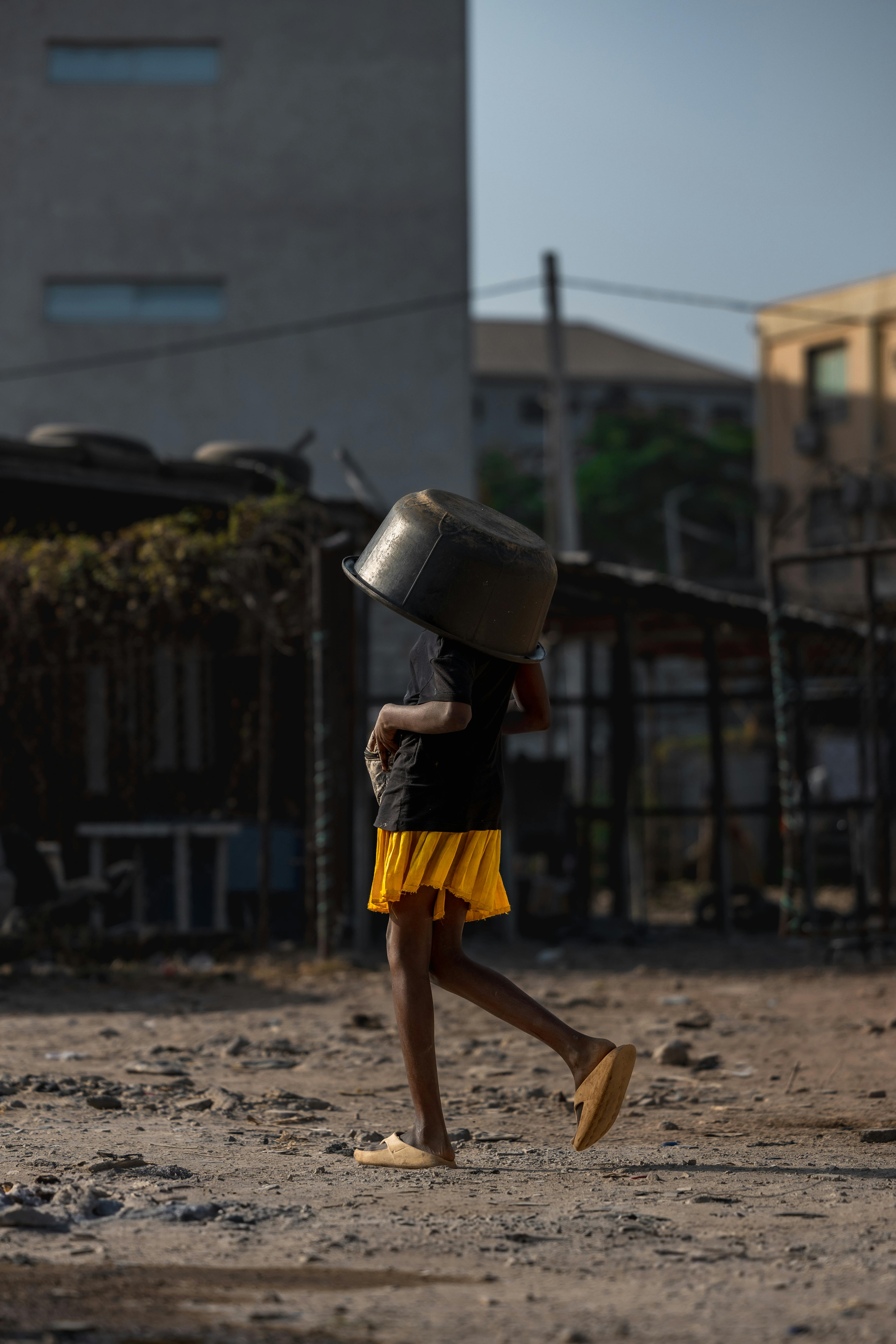 Young Girl with Pot on Head in Abuja Street Scene · Free Stock Photo