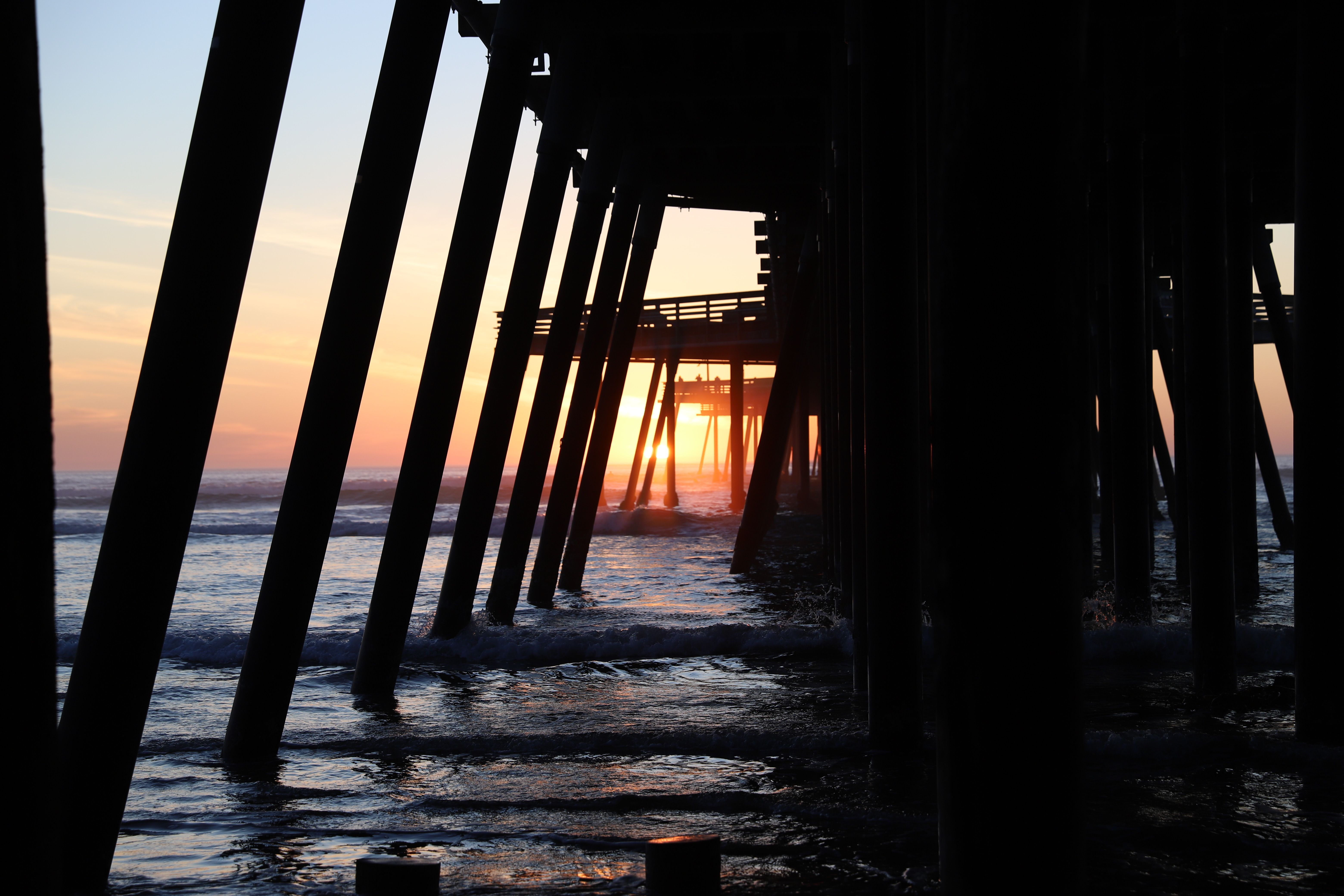 Sunset view through beach pier columns · Free Stock Photo
