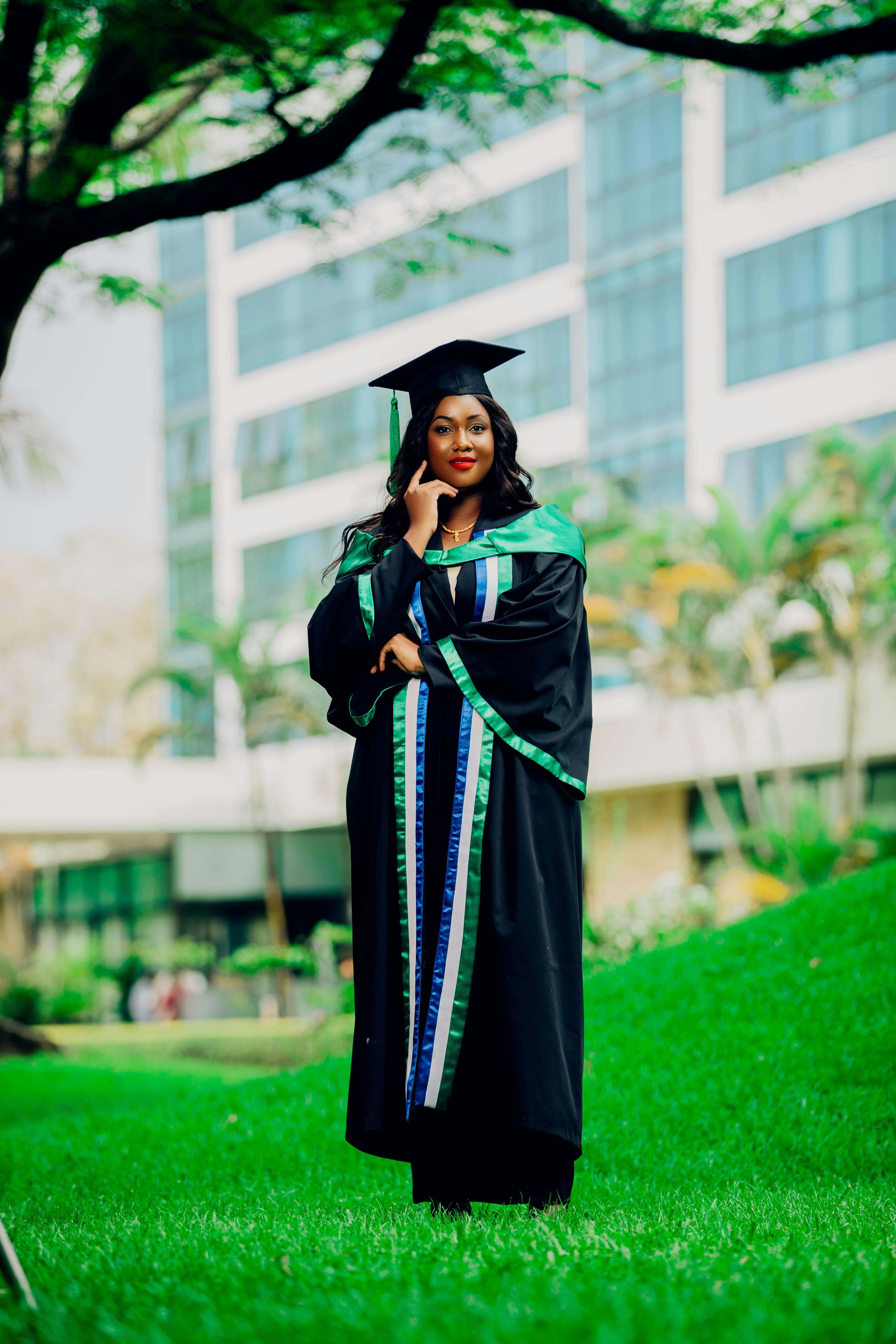 Proud Graduate Posing Outdoors in Cap and Gown · Free Stock Photo