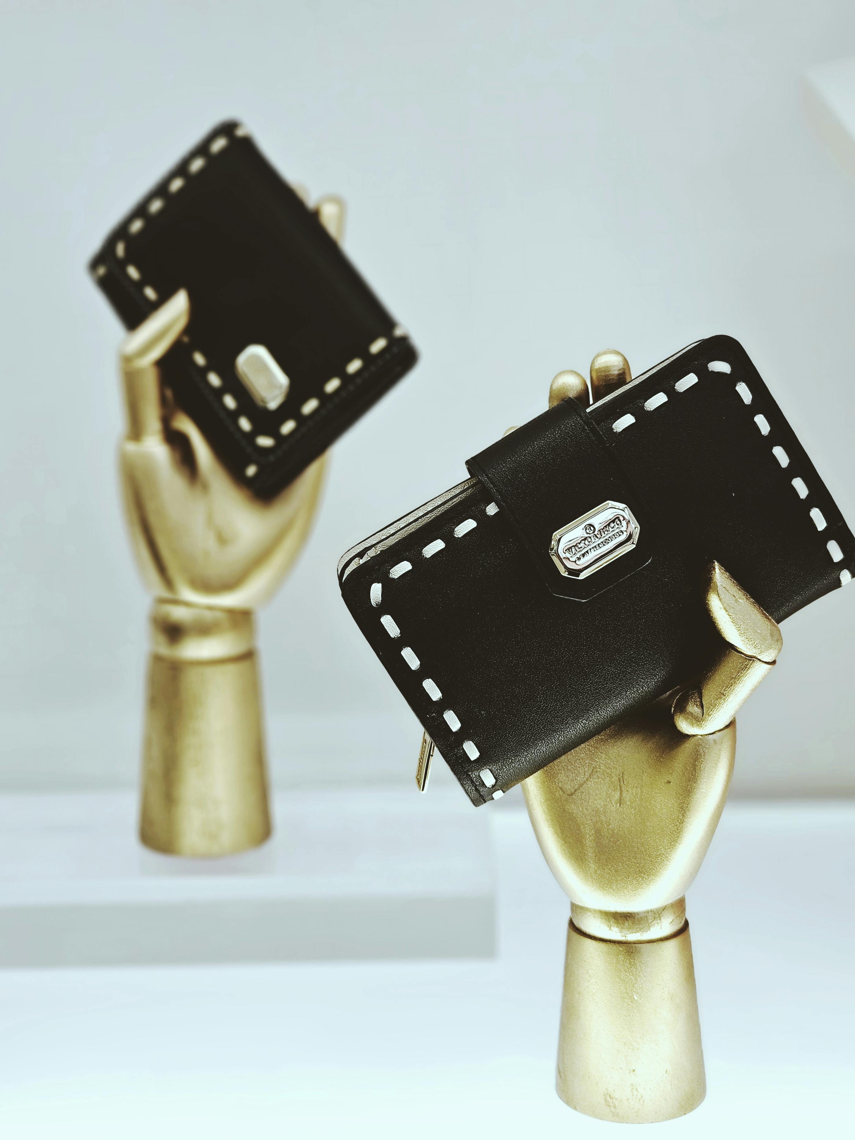 Elegant Display of Leather Wallets on Gold Stands · Free Stock Photo