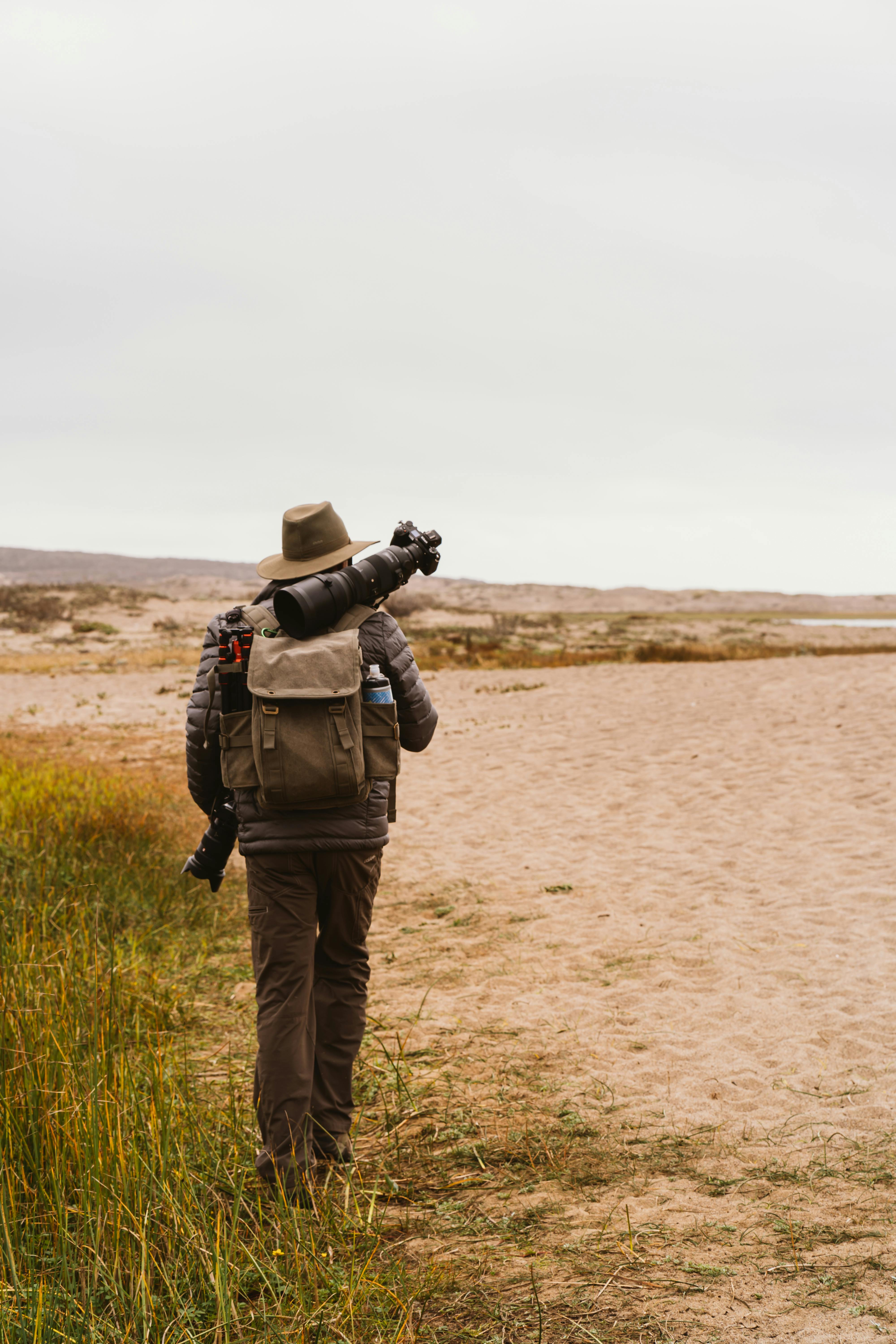 Man Holding and Looking at Dslr Camera on Camera Stand · Free Stock Photo