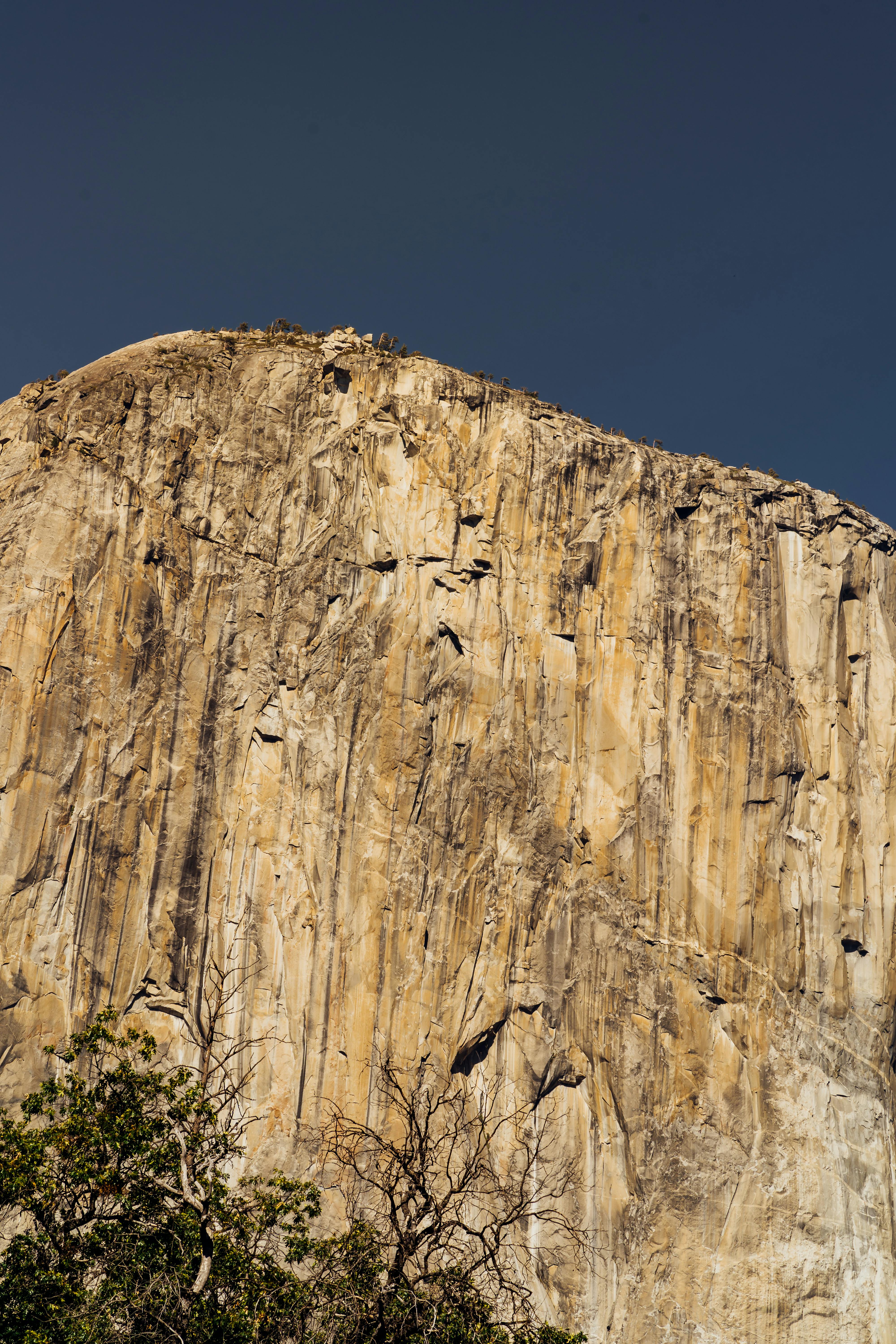 Low Angle Shot Of Rocky Mountain Cliff Under Blue Sky · Free Stock Photo