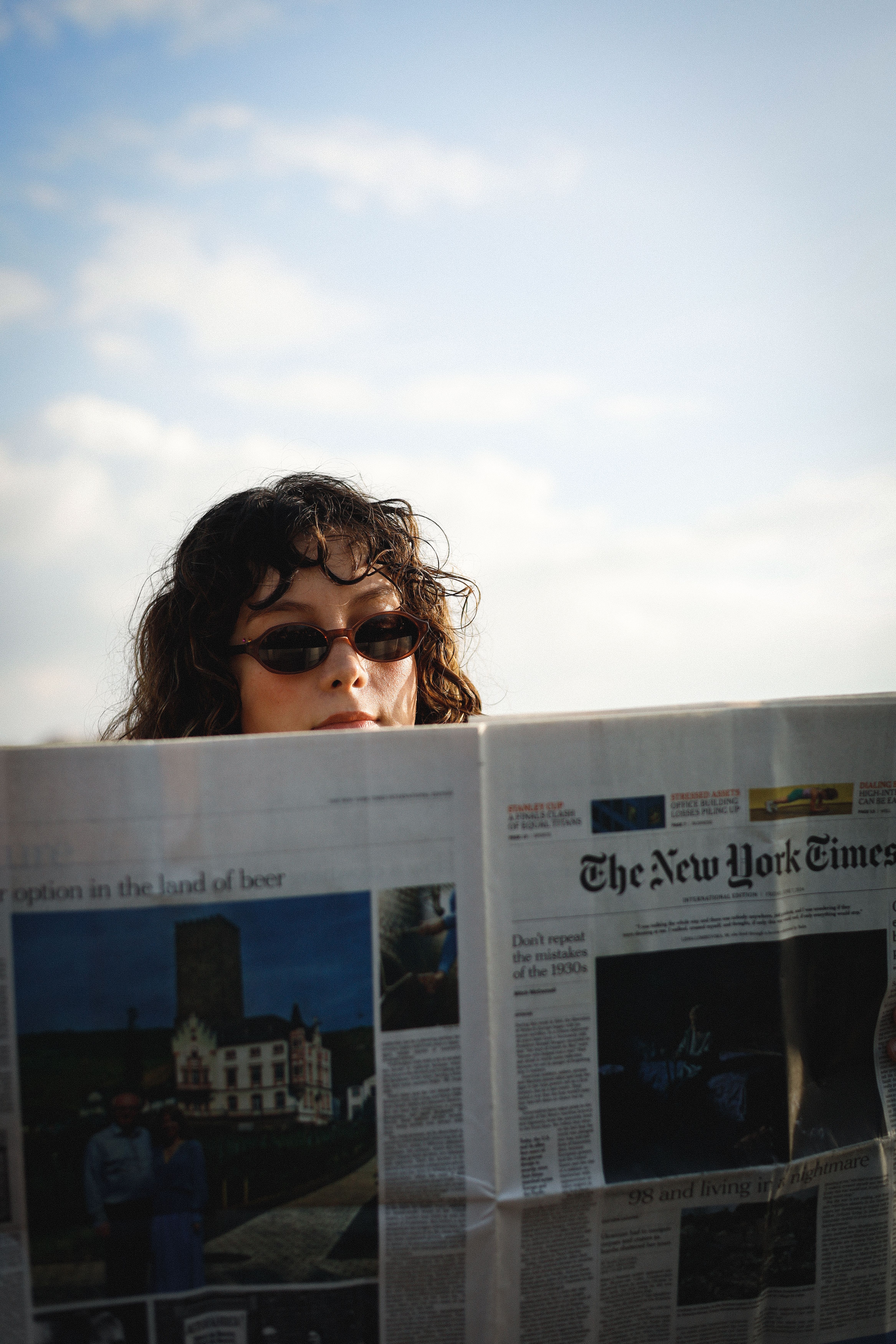Person Reading Newspaper Outdoors on a Sunny Day · Free Stock Photo