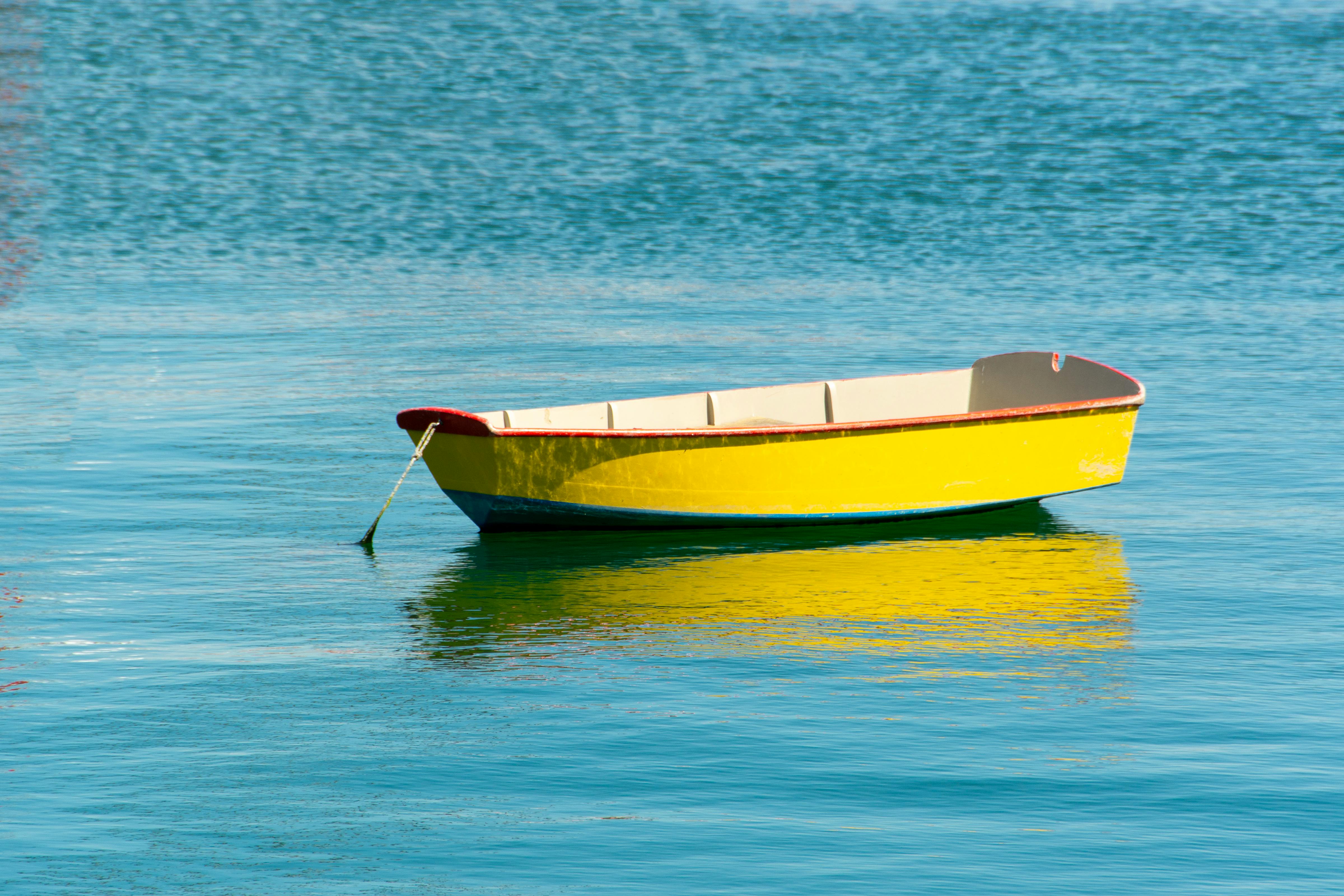 Vibrant Yellow Rowboat Floating on Clear Blue Water · Free Stock Photo