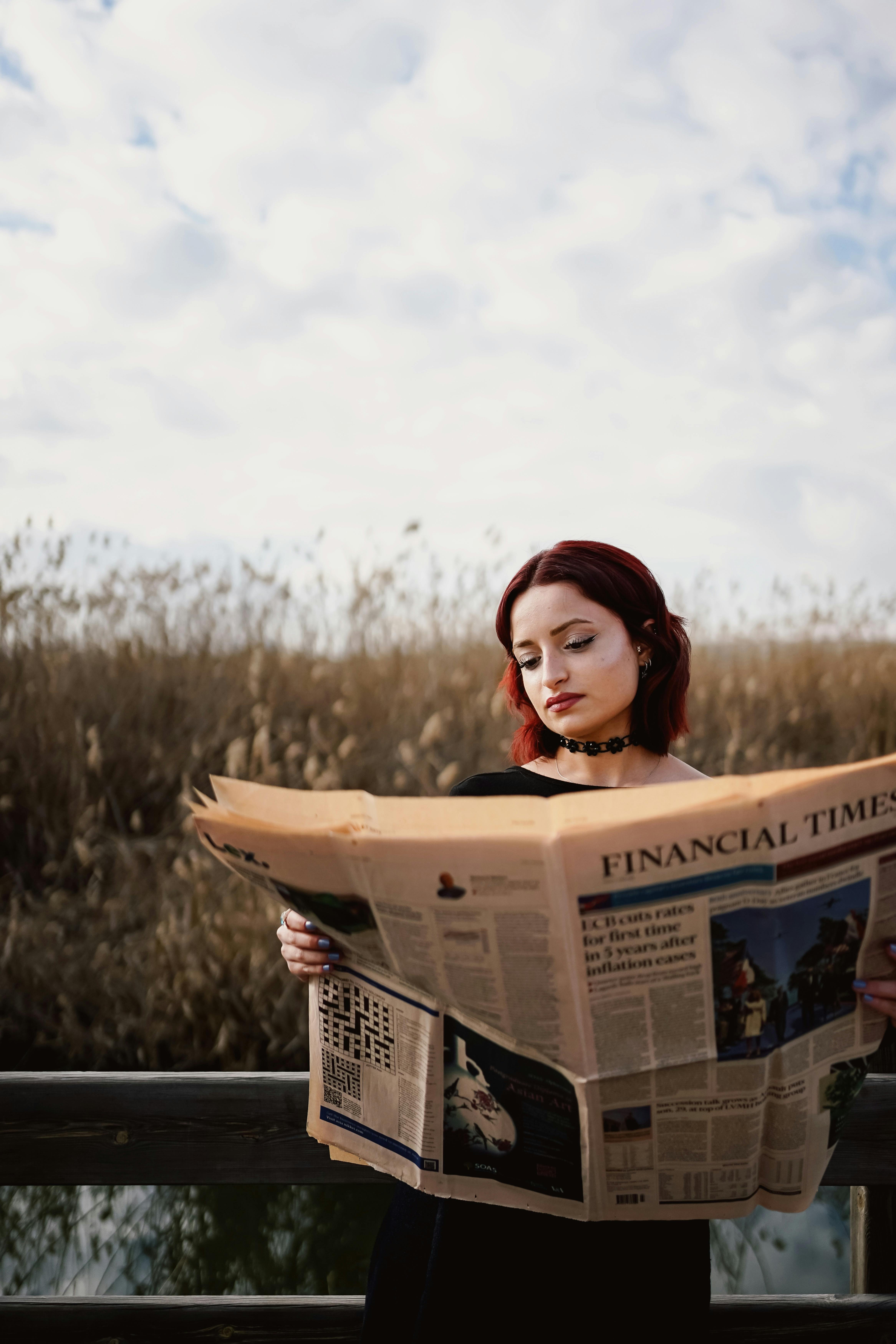 Young Woman Reading Financial Times Outdoors · Free Stock Photo