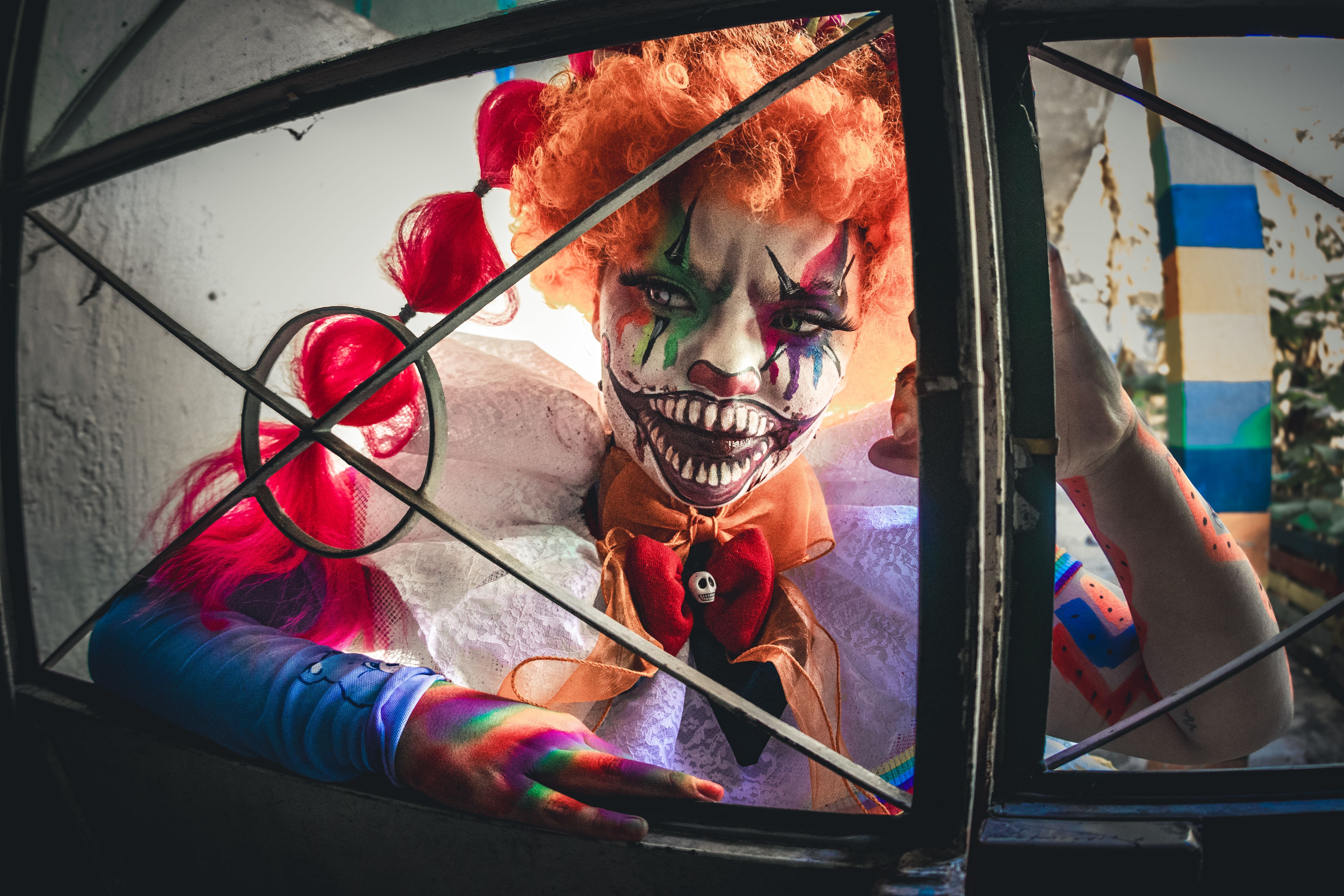 Colorful Clown in Horror Makeup Behind Window · Free Stock Photo