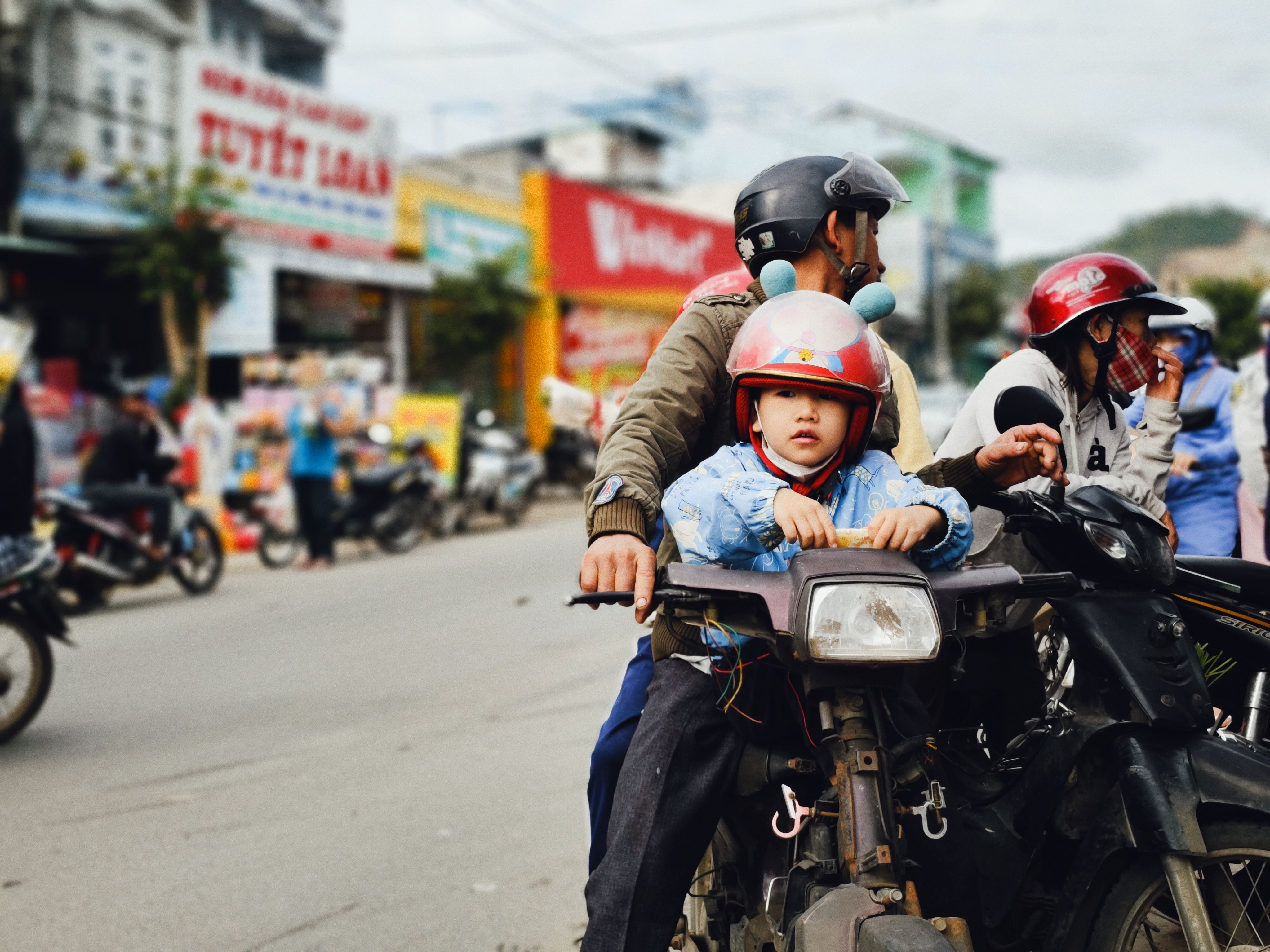 Child Riding on Motorcycle Through Busy Street · Free Stock Photo
