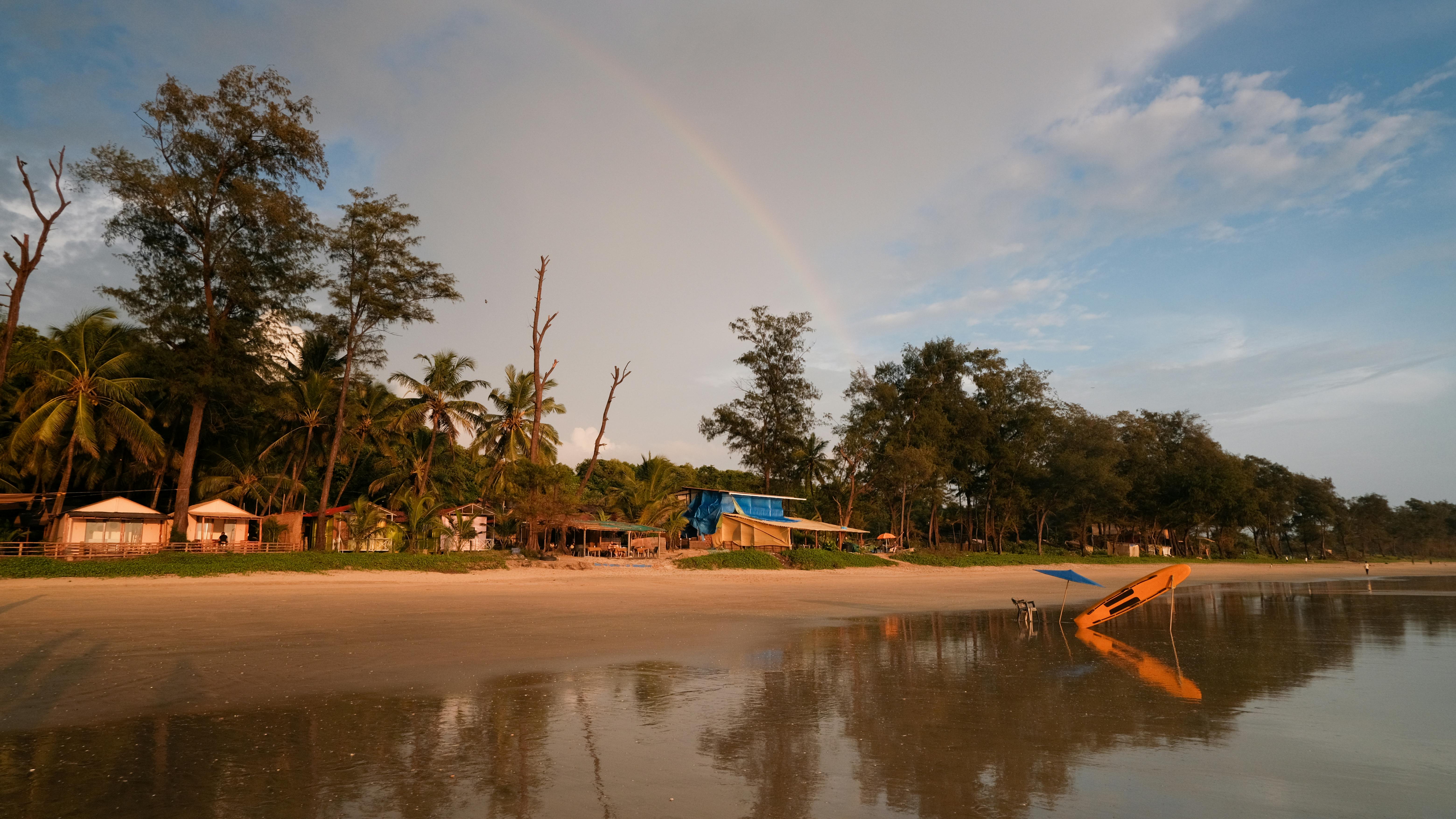 Serene Beachfront with Rainbow and Reflection · Free Stock Photo