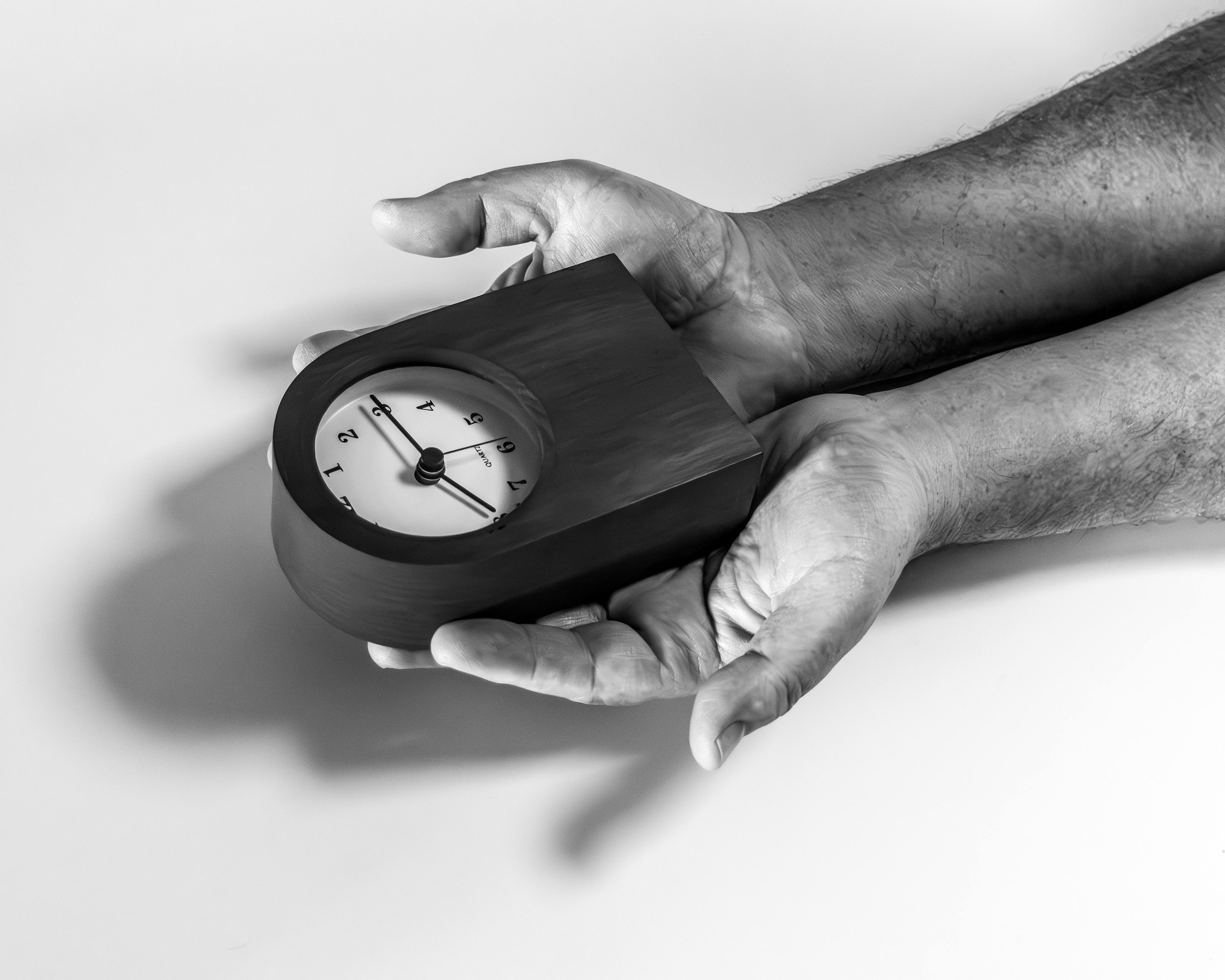 Black and White Hands Holding a Clock · Free Stock Photo