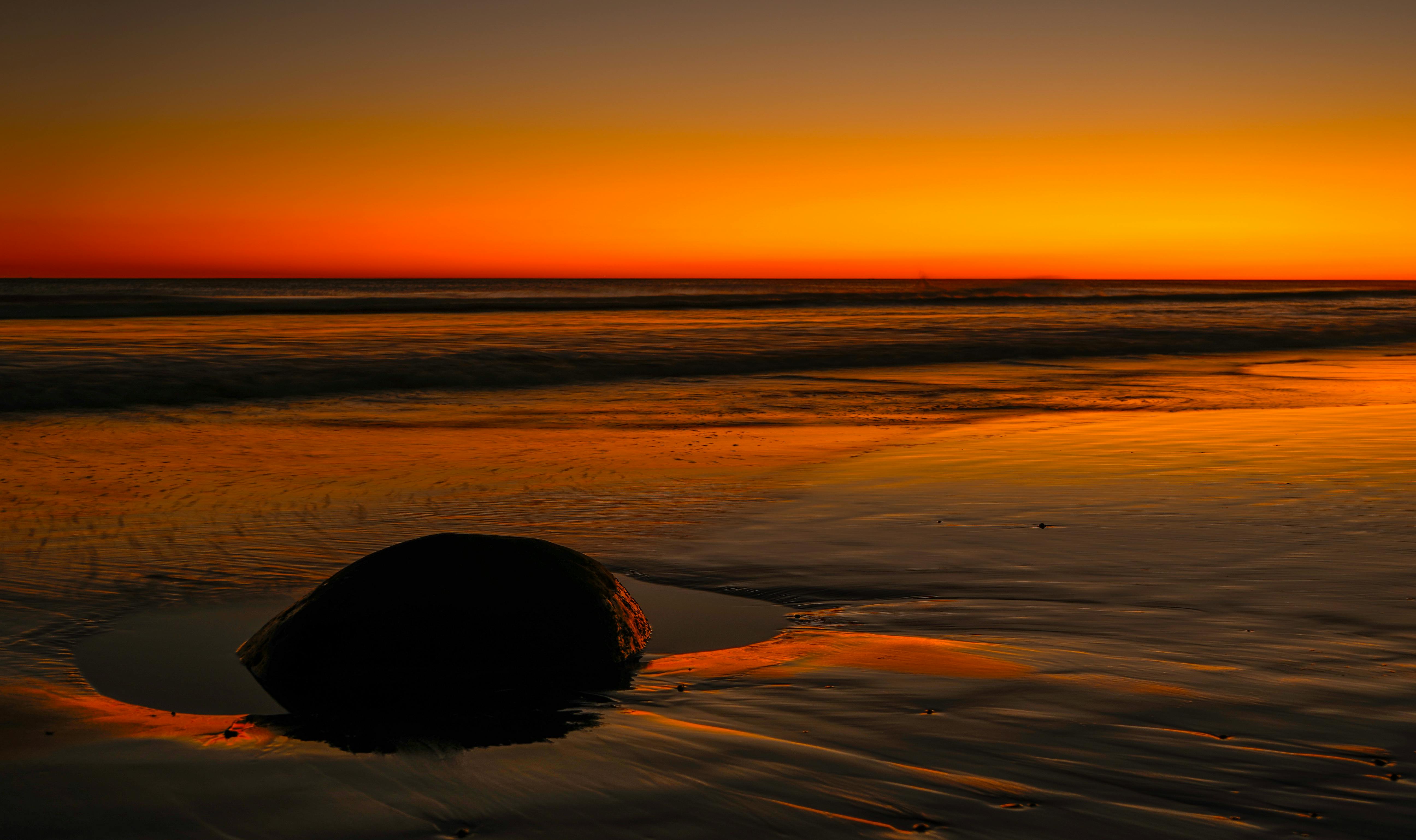 Serene Beach Sunset with Rock Formation · Free Stock Photo