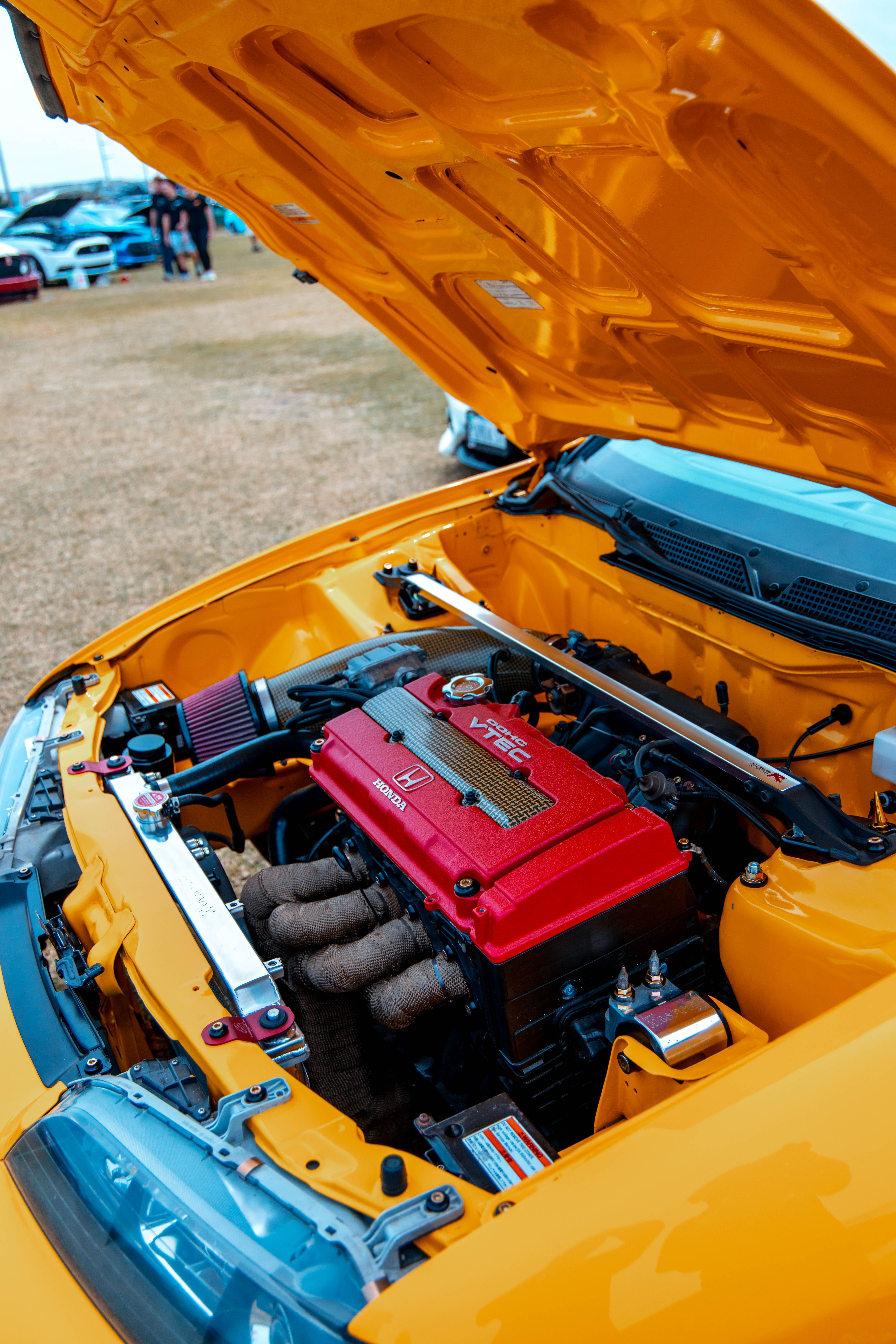 Open hood of a modified yellow car with red engine · Free Stock Photo
