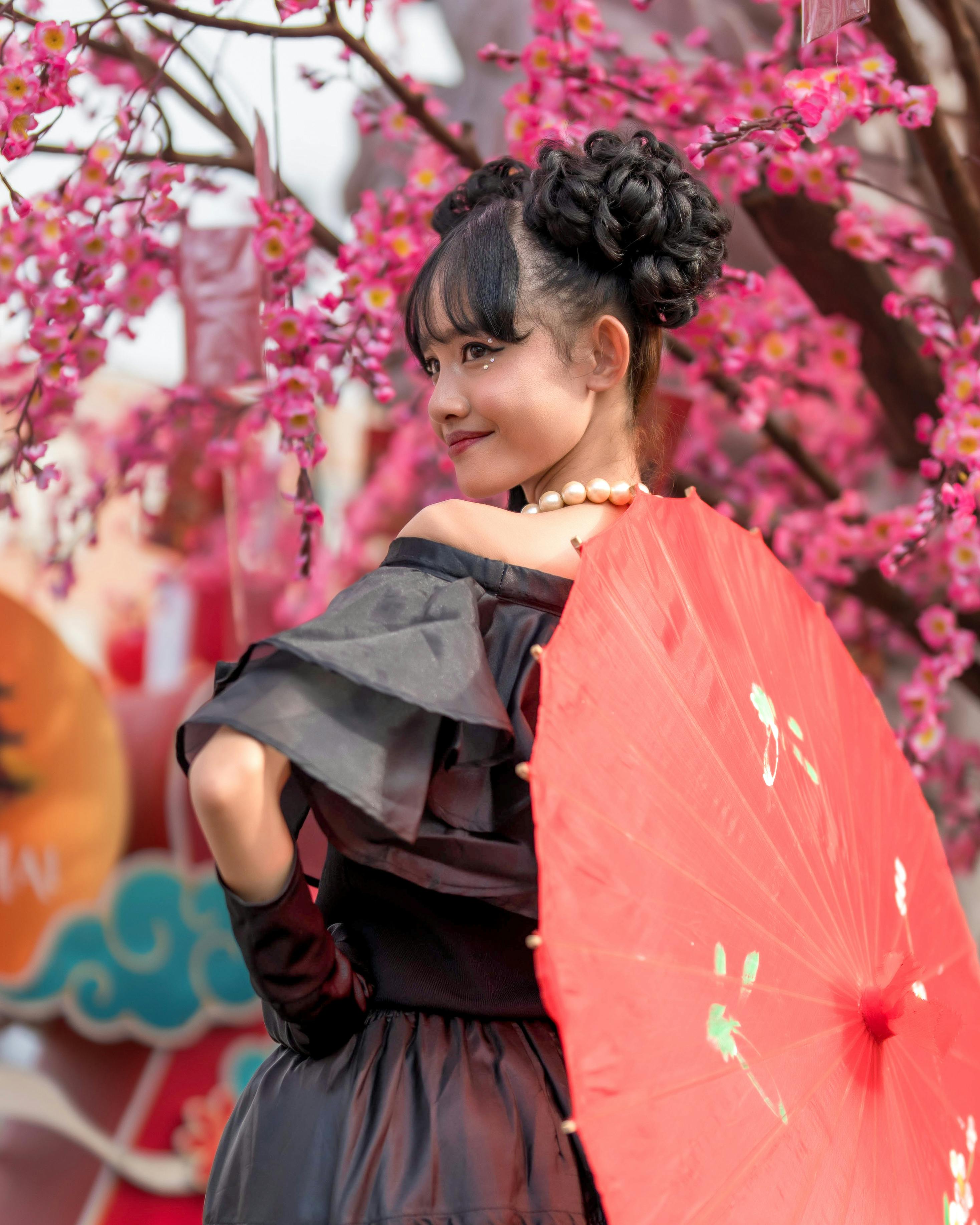 Elegant Woman with Red Parasol in Cherry Blossom Setting · Free Stock Photo